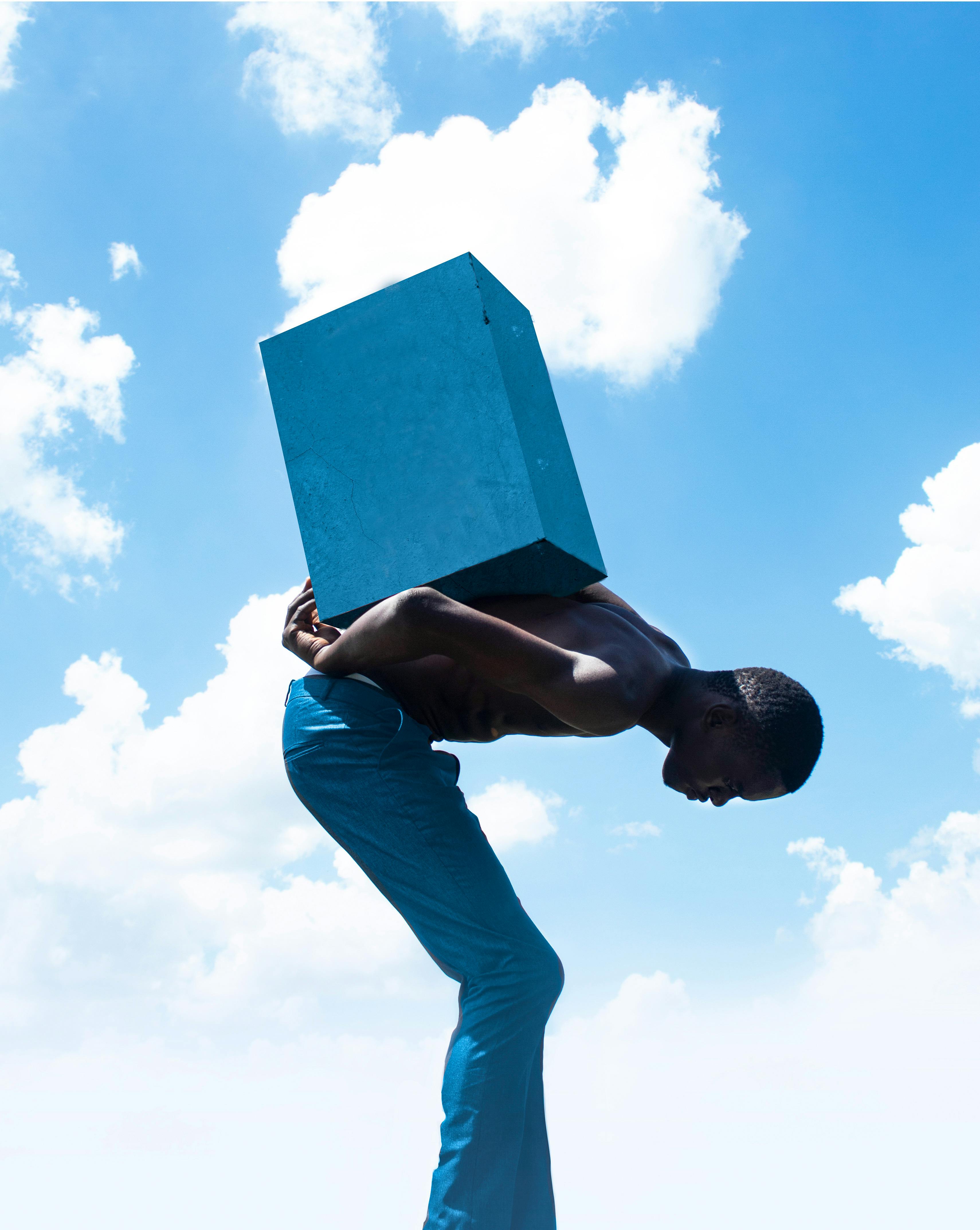 A Shirtless Man Carrying a Concrete Block on His Back · Free Stock Photo