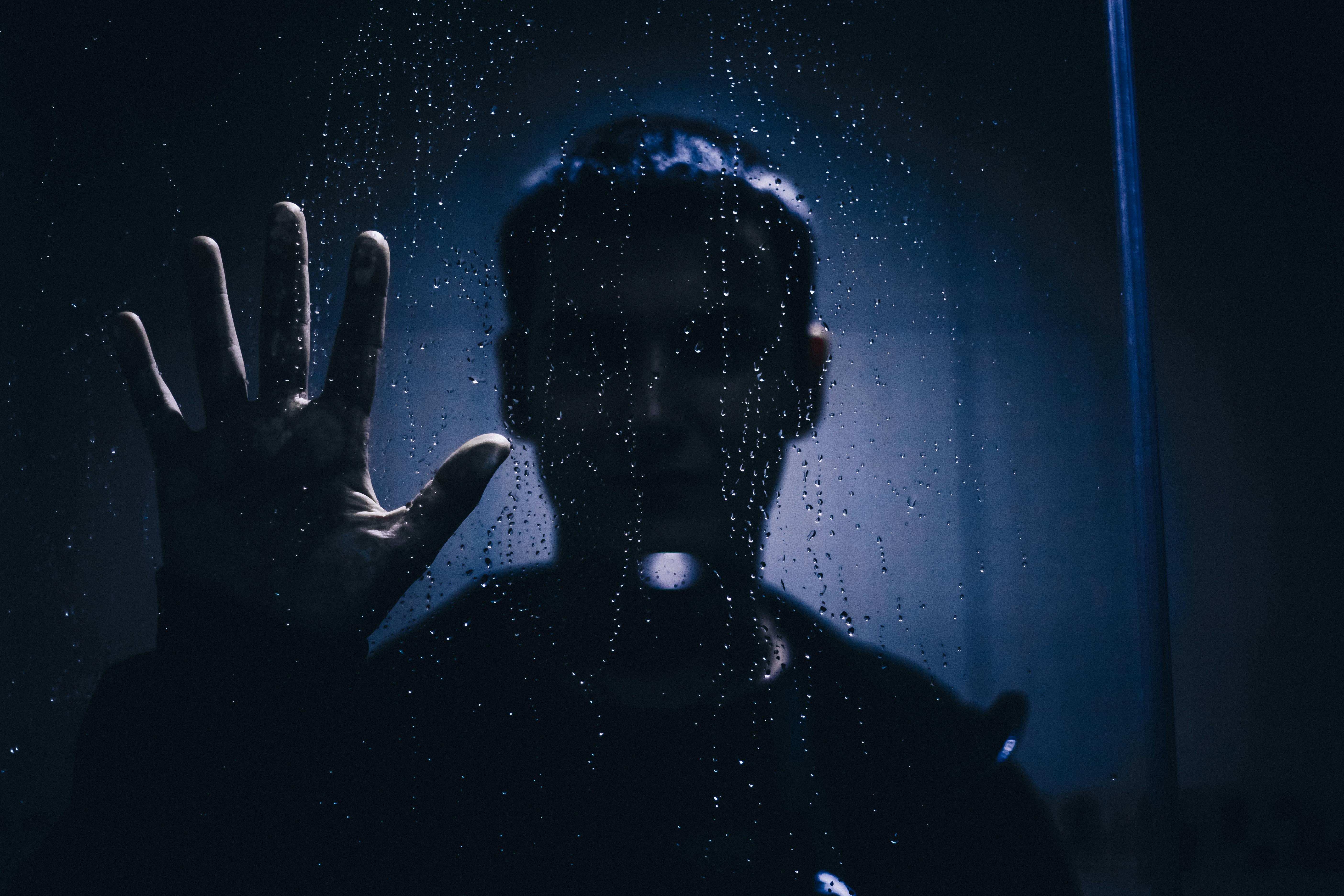 Person in the Dark Standing Near the Glass Wall · Free Stock Photo