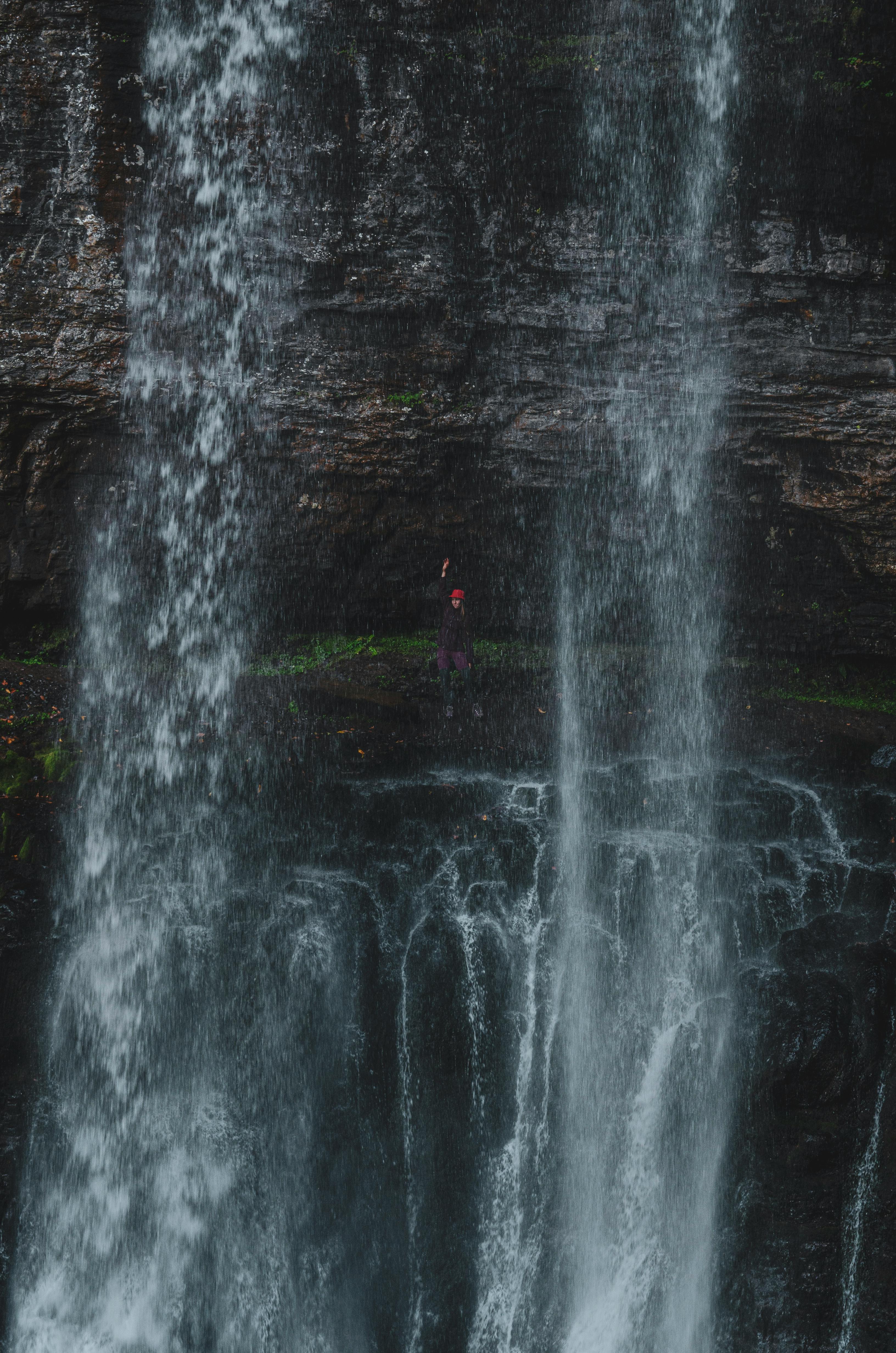 Person Standing under Flowing Water of Waterfall · Free Stock Photo