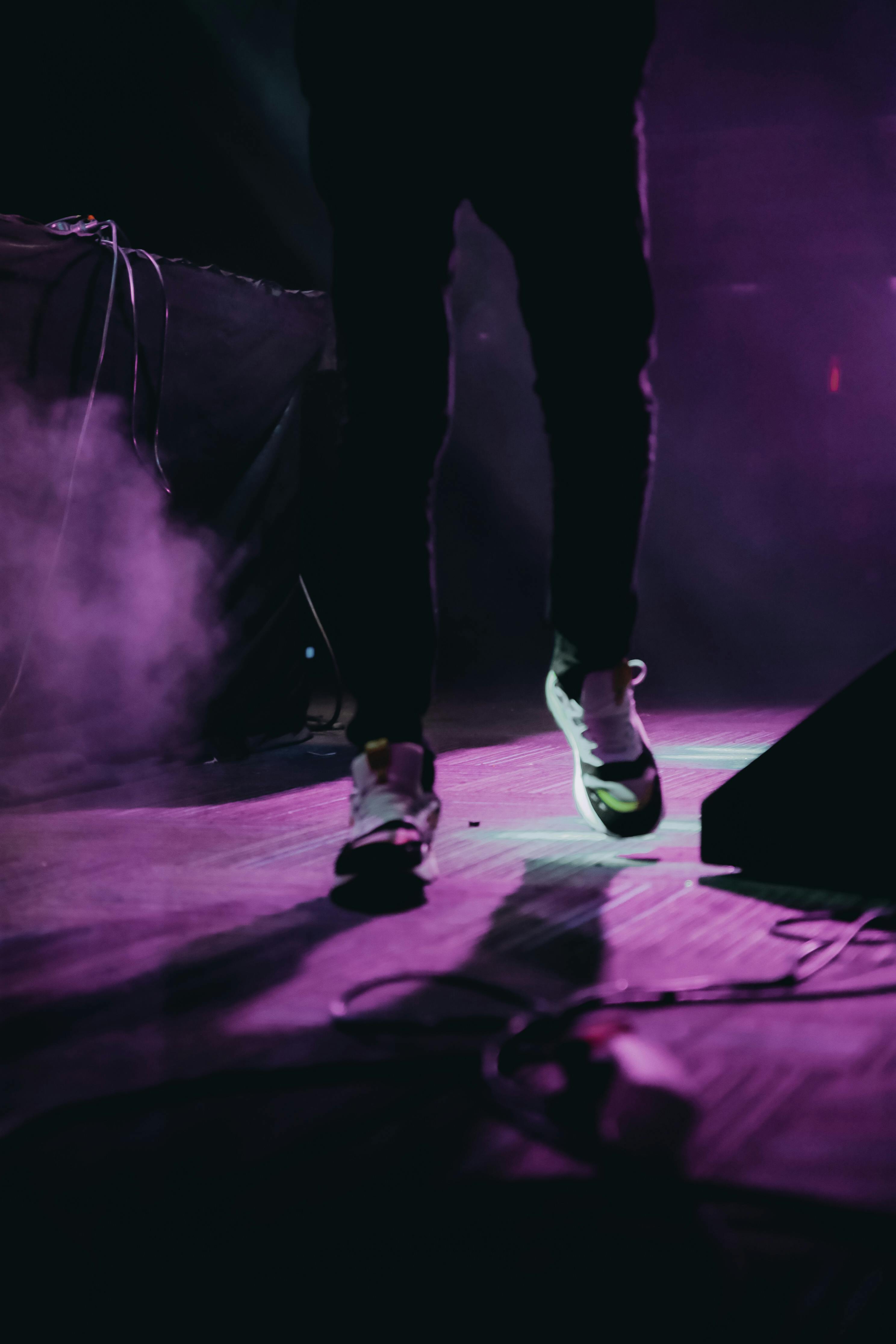 Person in Black Pants and Sneakers Standing on Stage · Free Stock Photo
