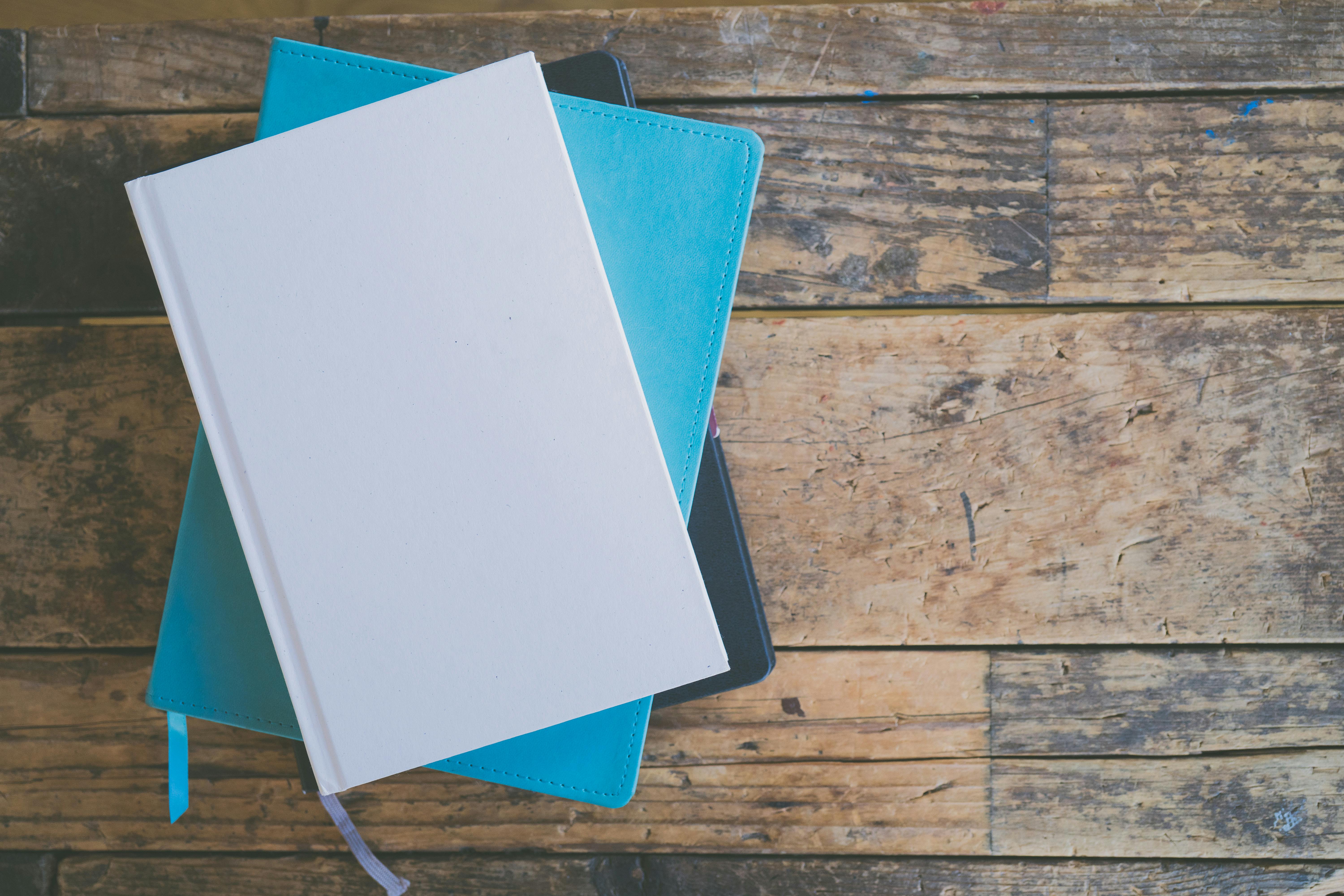 Stacks of Notebooks on Brown Wooden Surface · Free Stock Photo