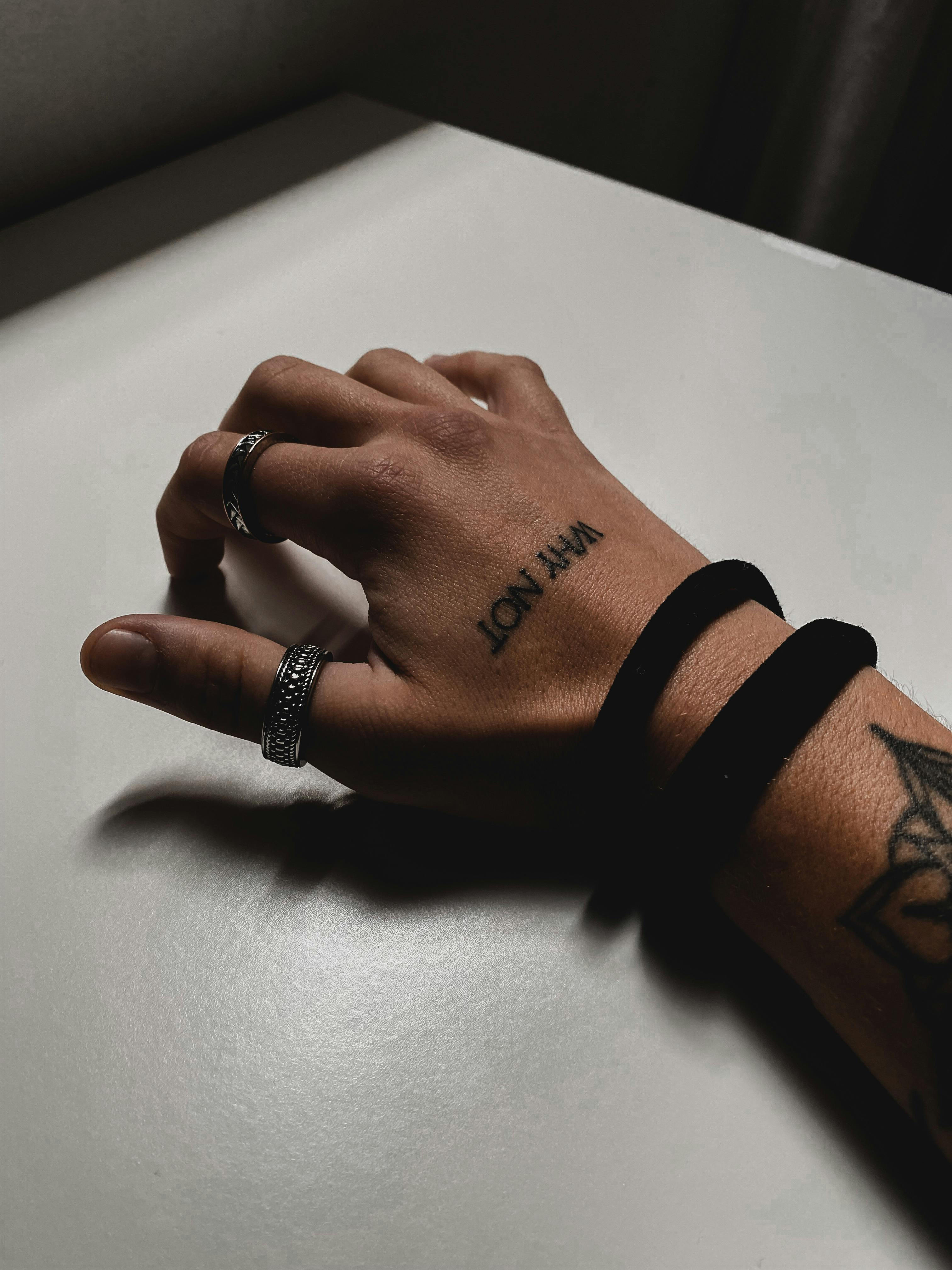 Person Wearing Silver Ring on White Table · Free Stock Photo