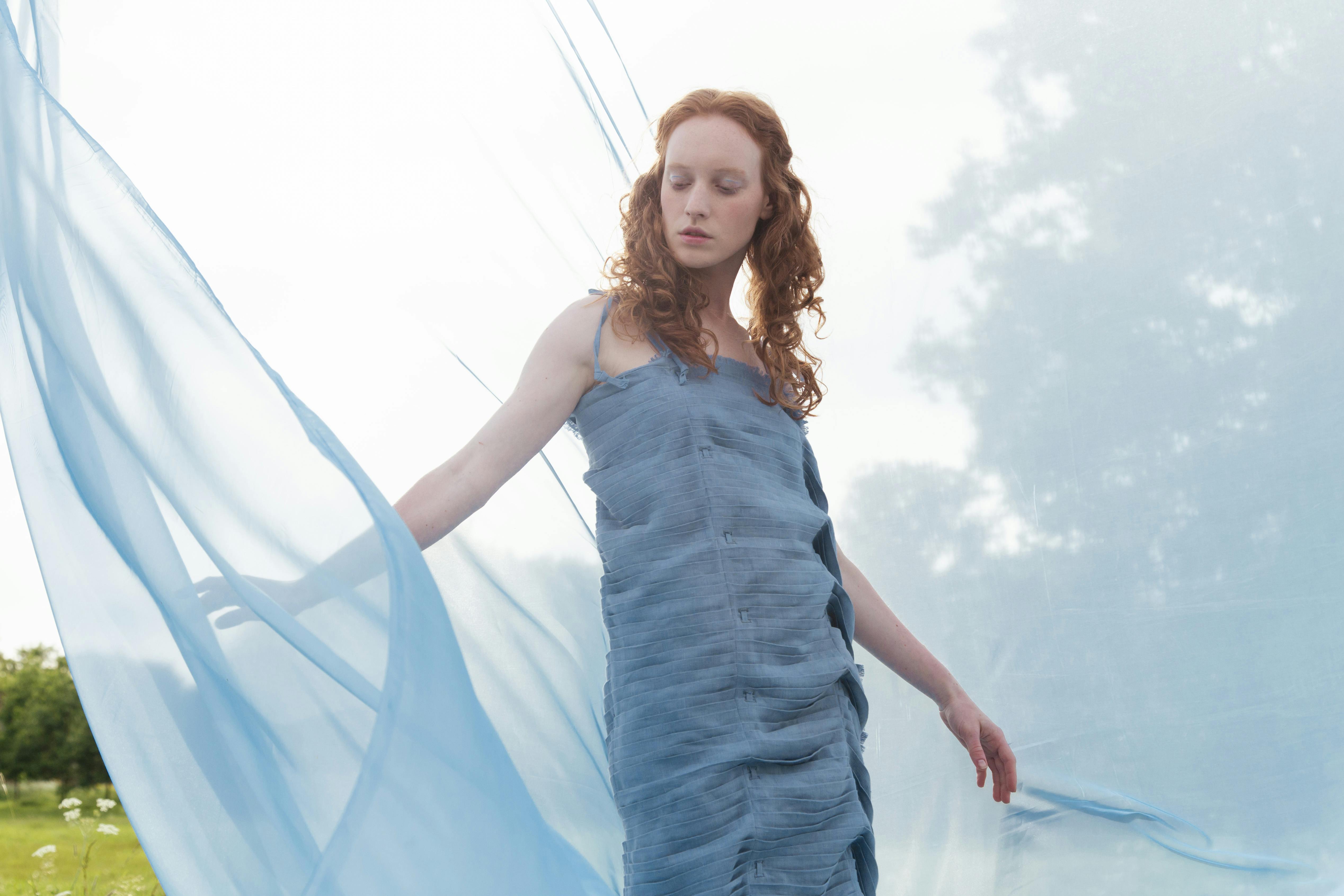 Woman Looking Down While Standing Beside Tree Trunk · Free Stock Photo