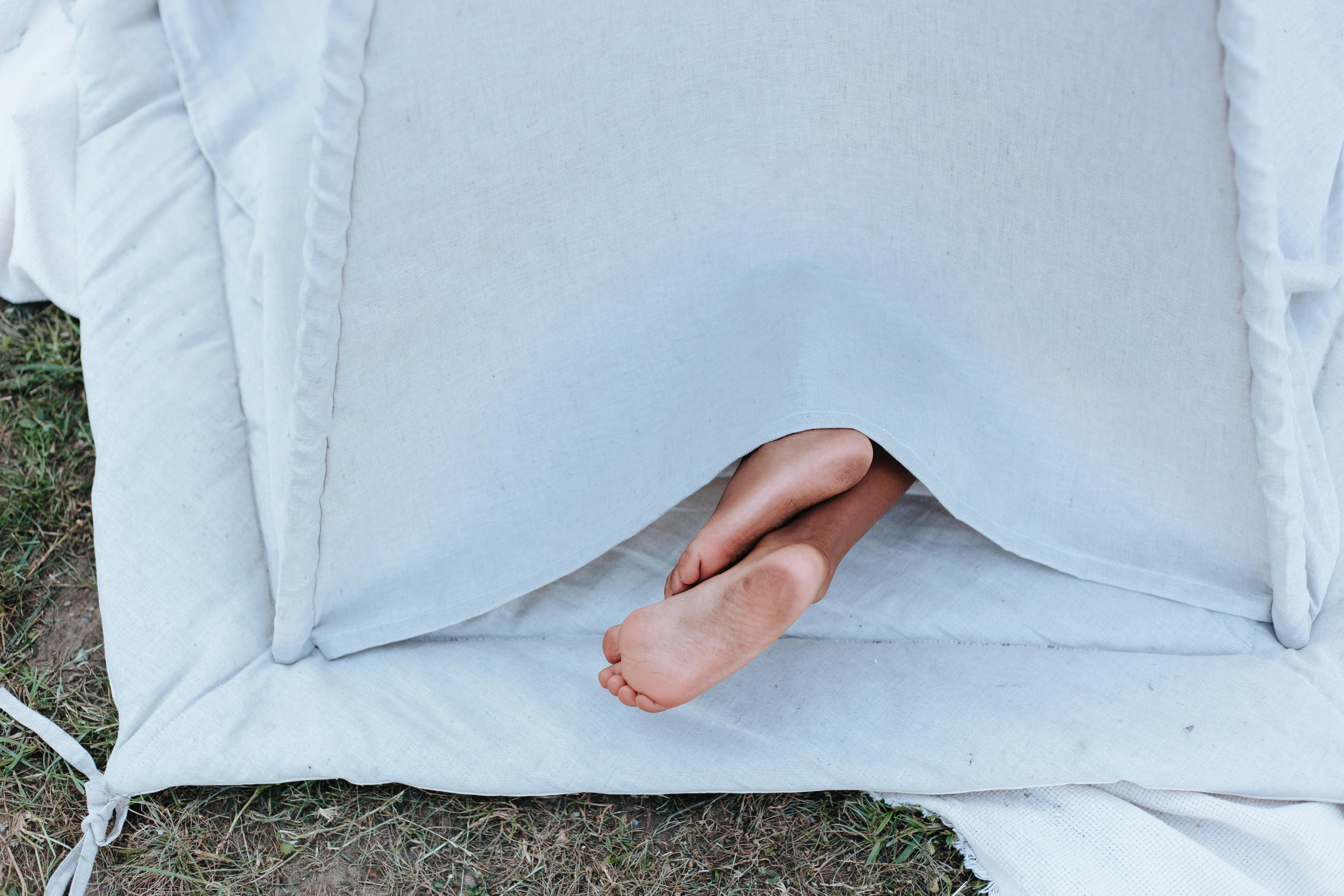 Feet Sticking Out from Under the Cover · Free Stock Photo