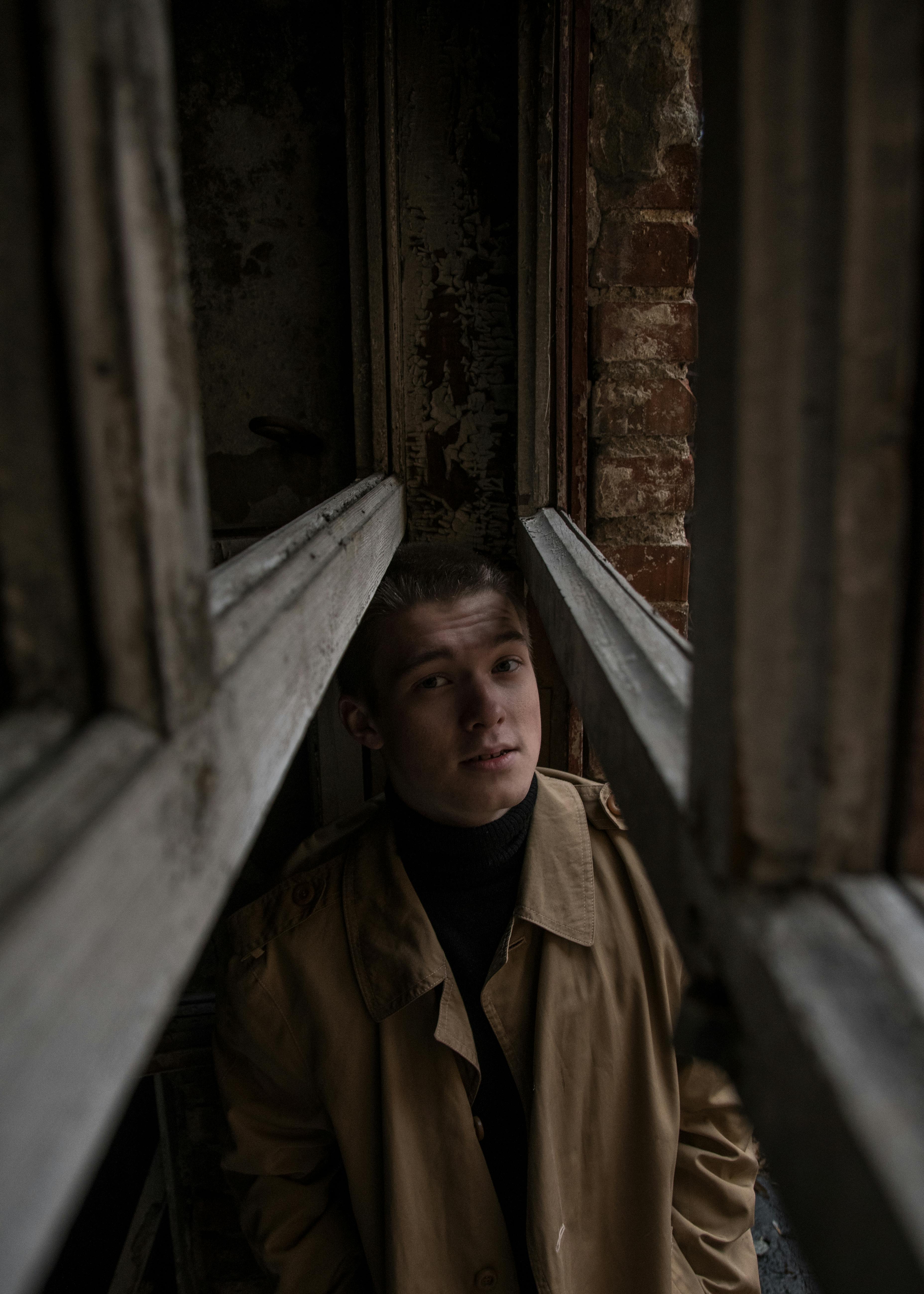 A Man Standing by a Window in an Abandoned Building · Free Stock Photo