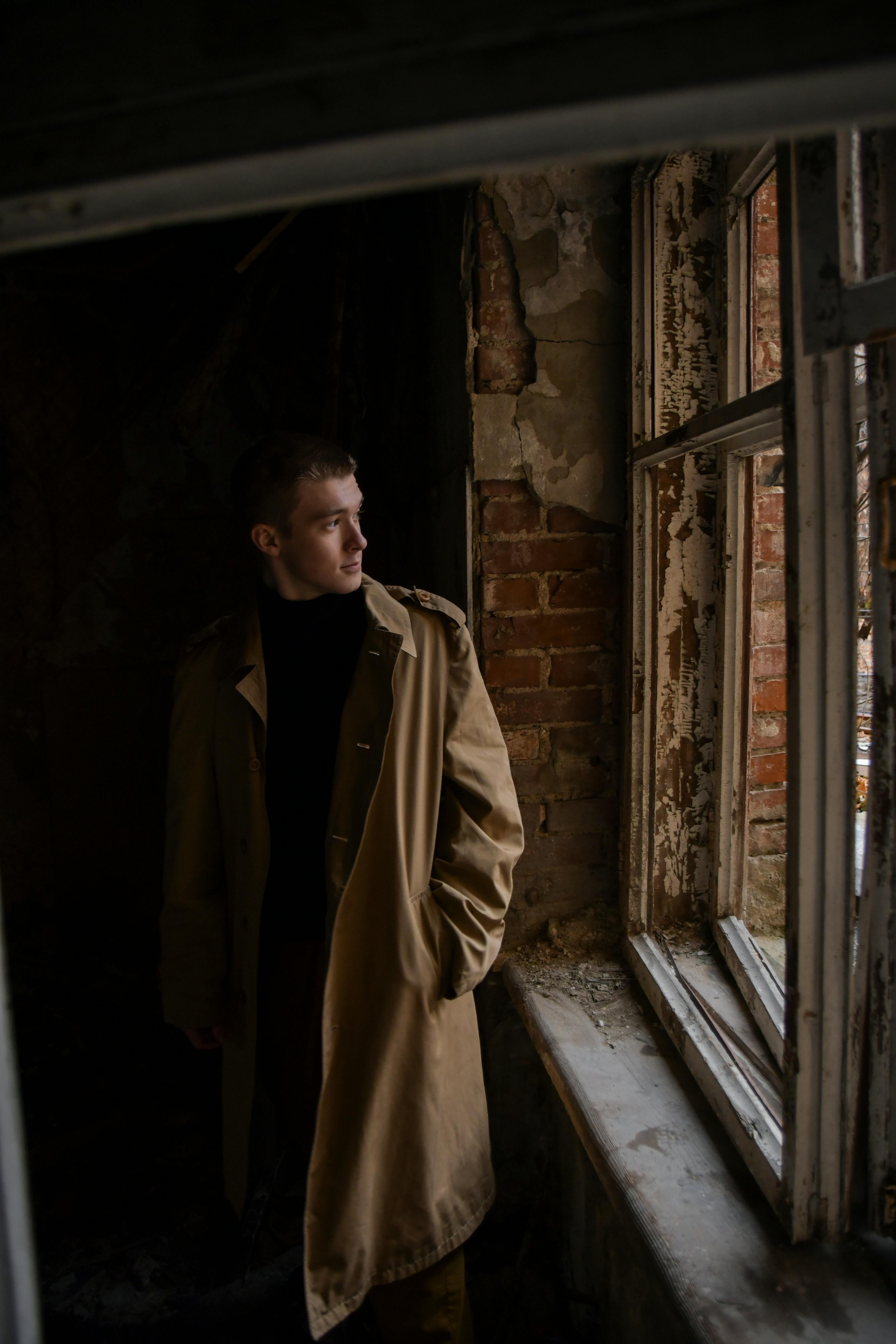 Man in Brown Coat Standing Beside Window · Free Stock Photo