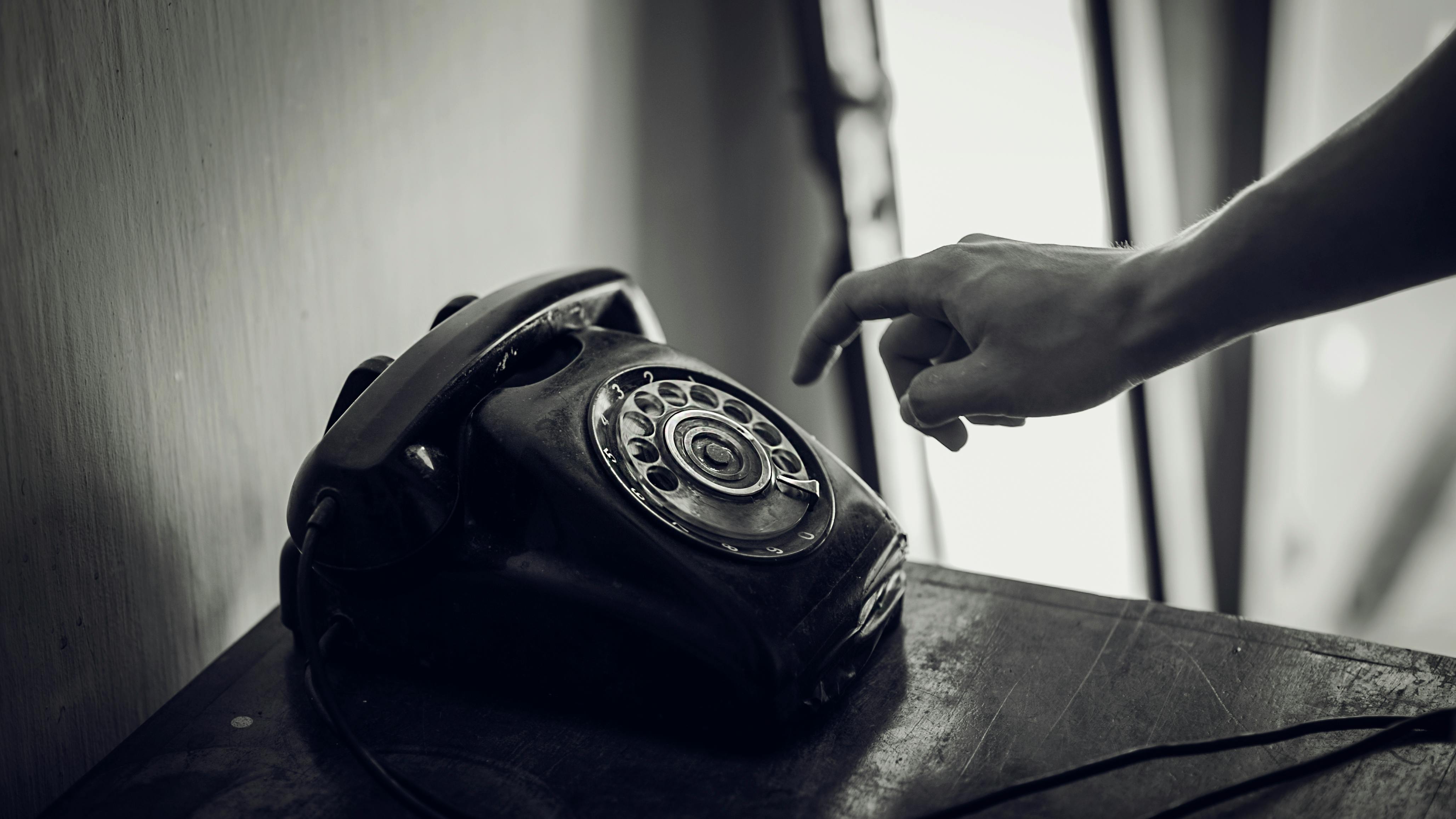 Grayscale Photo of Rotary Telephone Beside Person Hand · Free Stock Photo