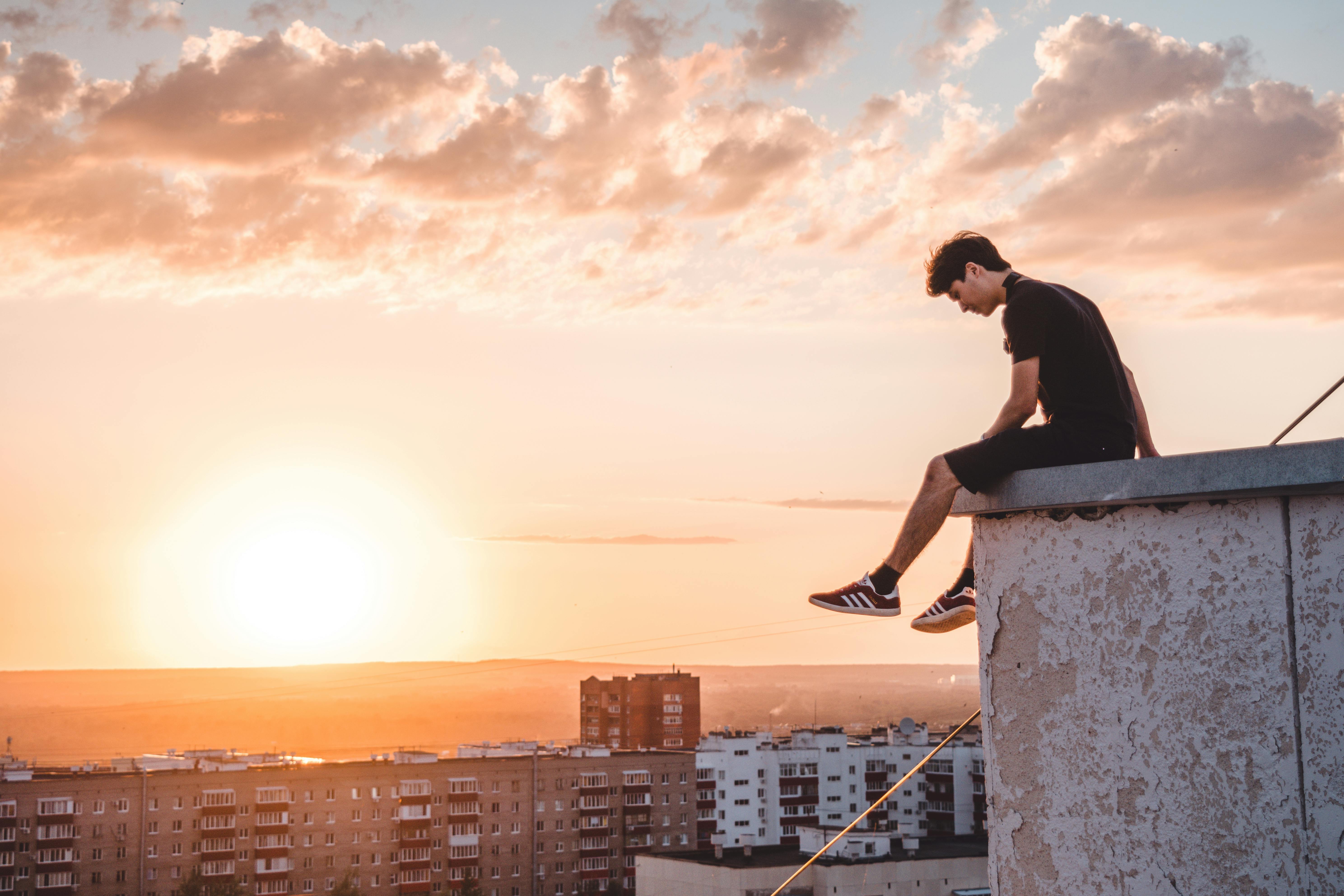Photo of a Man Sitting on the Ledge of a Building · Free Stock Photo