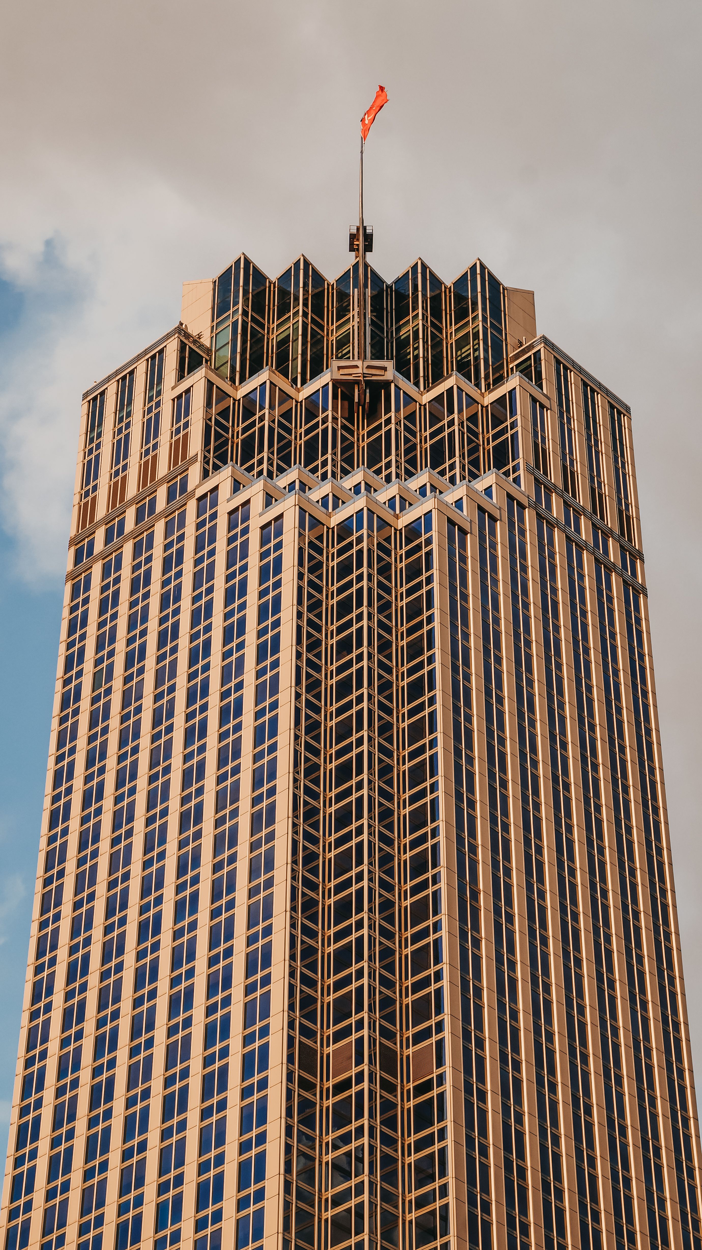 A Low Angle Shot of a Tower with Flag on Top Under the Cloudy Sky ...