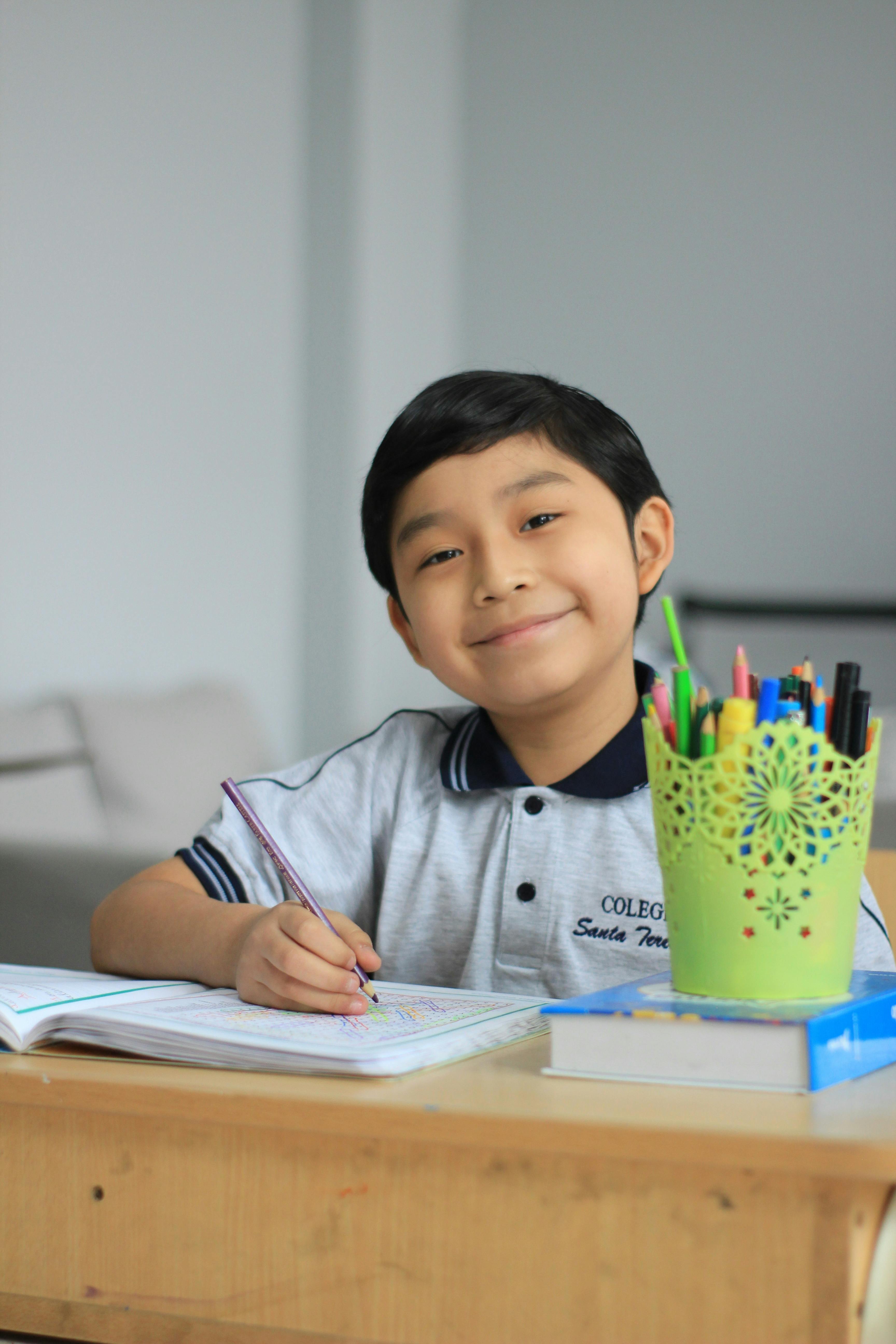 Smiling Child Studying at Home Desk · Free Stock Photo
