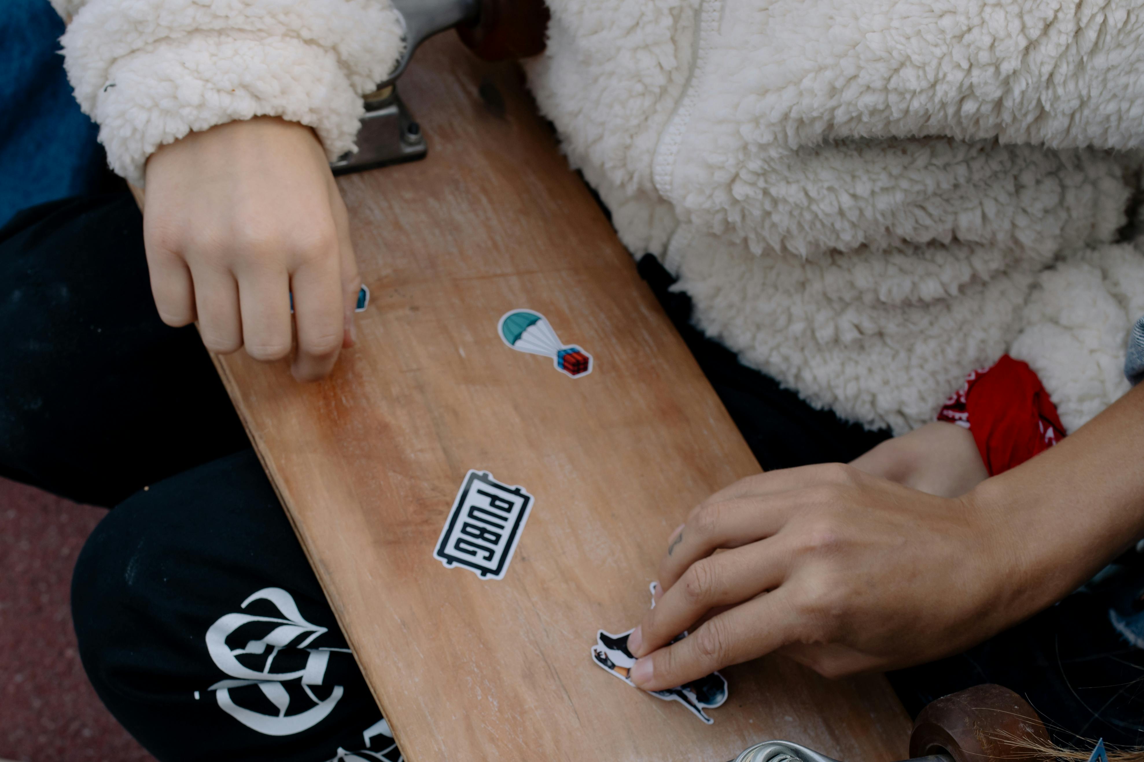 Close-Up Shot of a Person Putting Stickers on a Skateboard · Free Stock ...