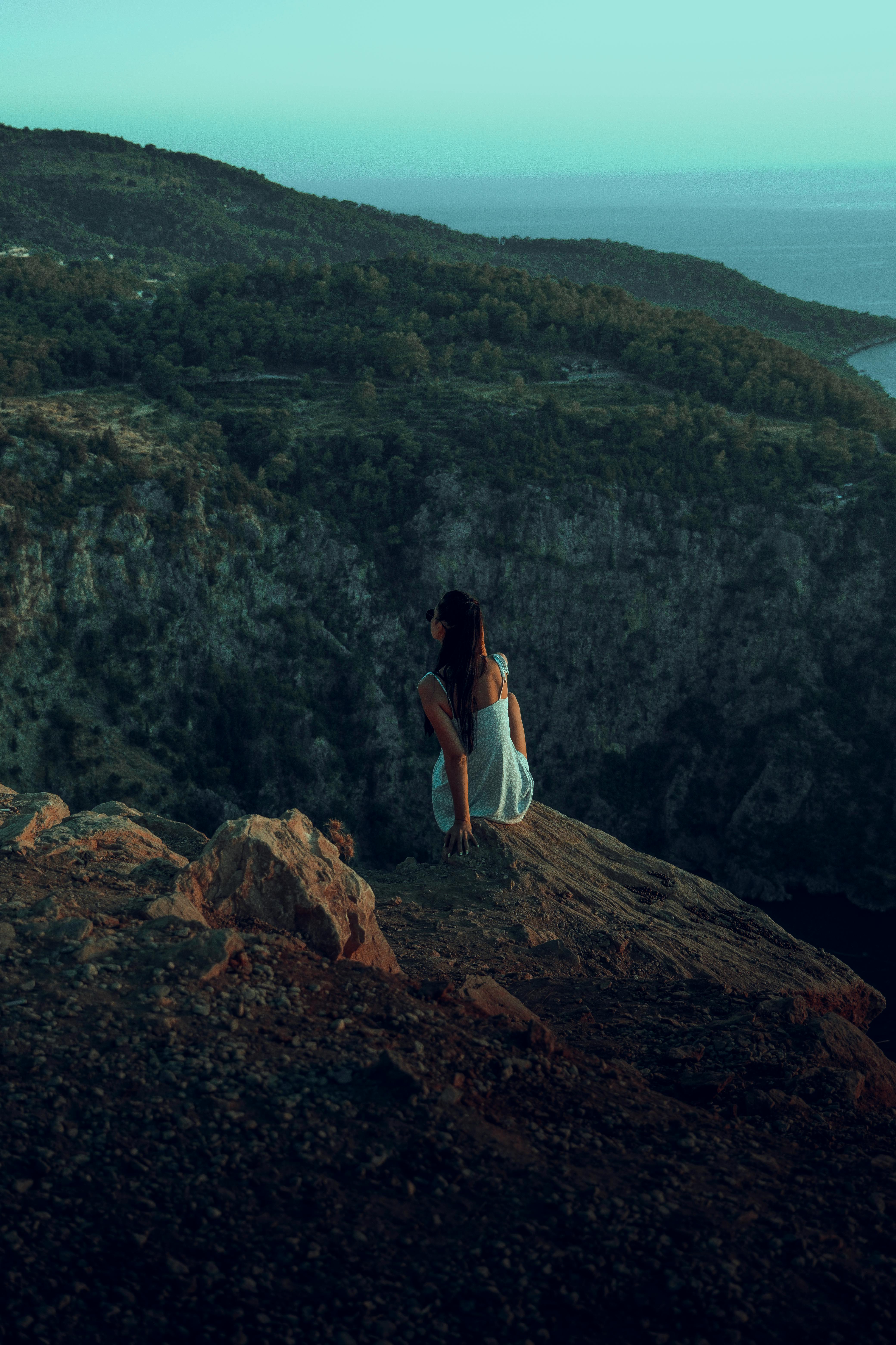 Back View of a Woman Sitting on a Cliff · Free Stock Photo