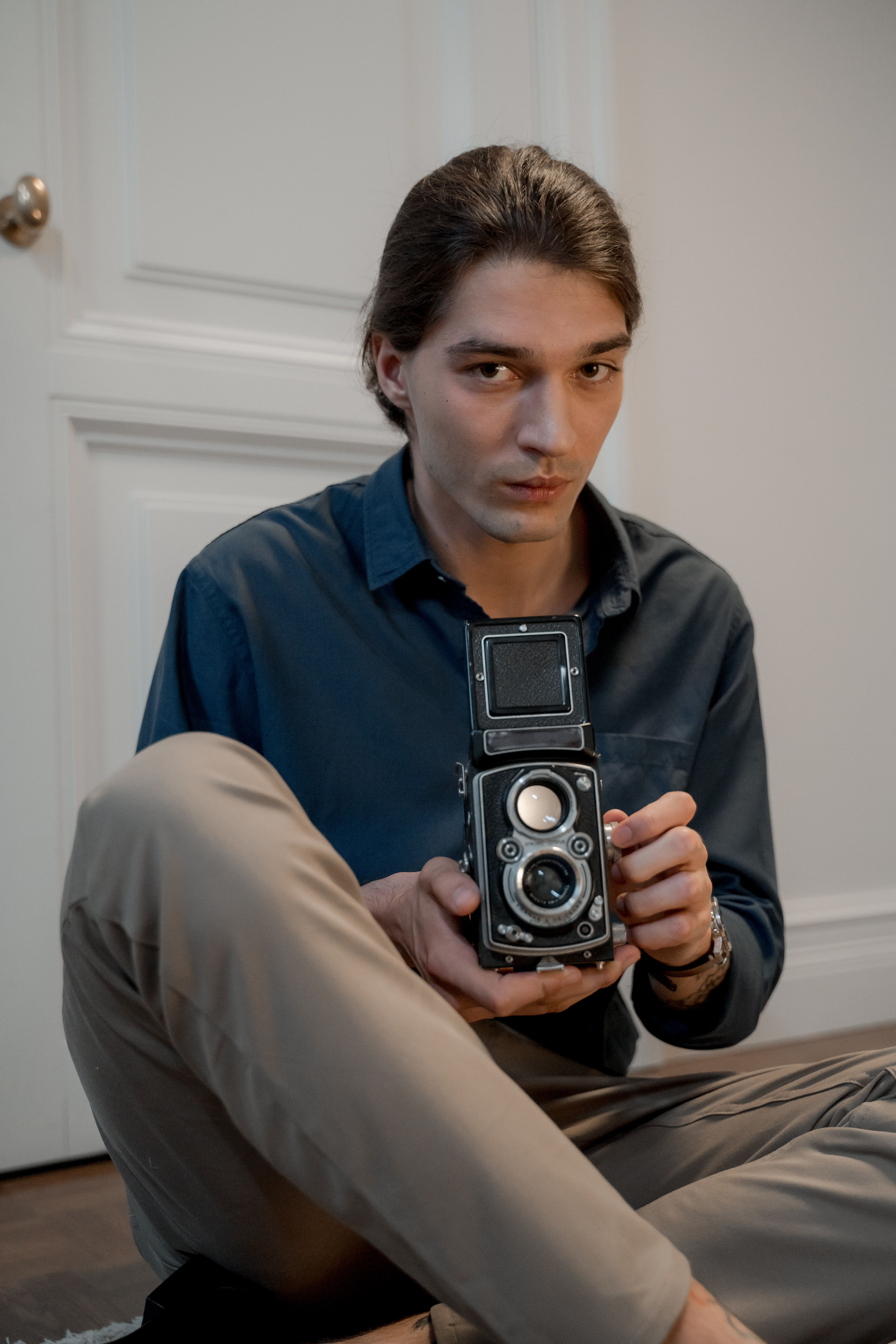 Man Holding Analog Camera Sitting on Floor · Free Stock Photo