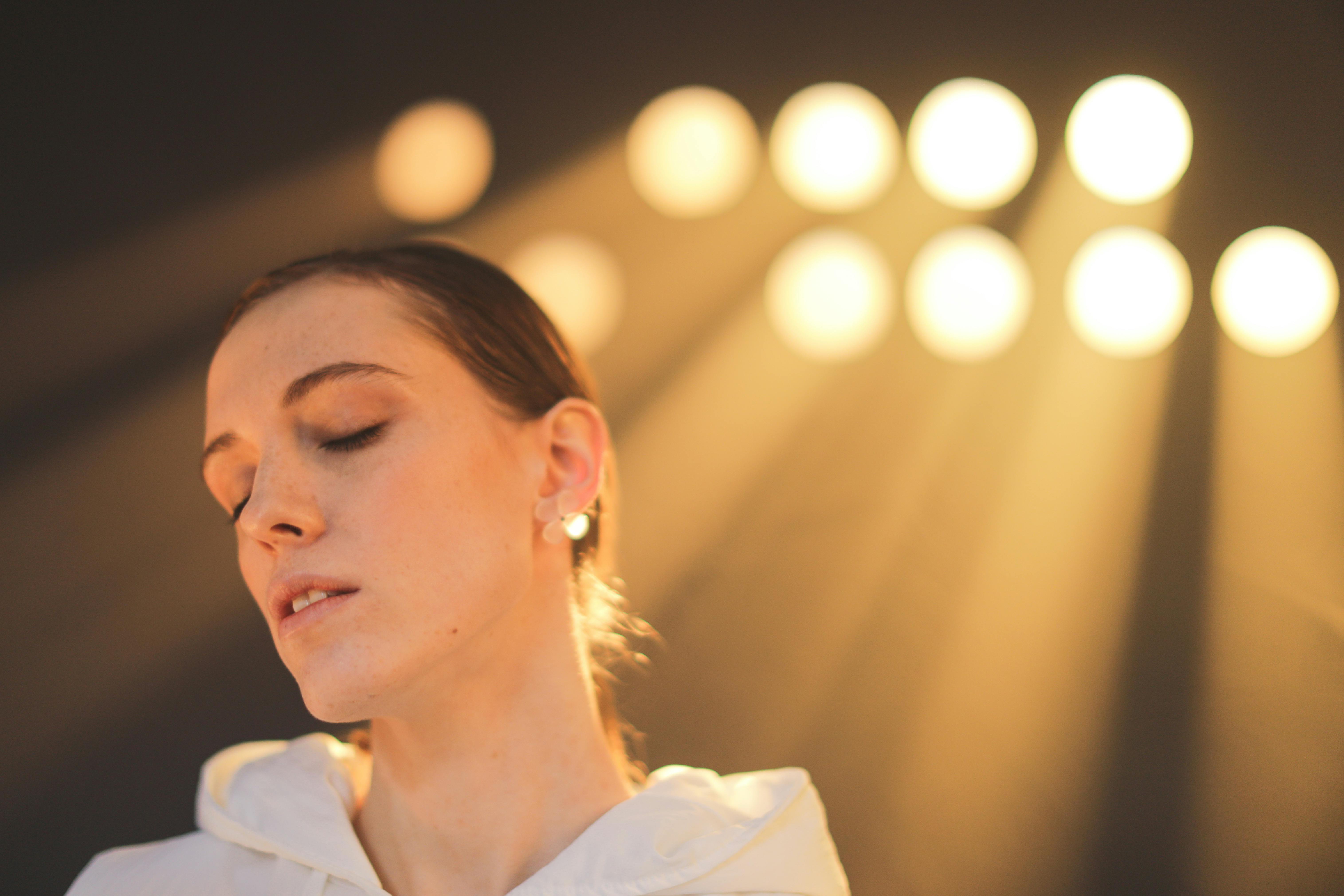 A Woman Lit by a Spotlight in the Dark Room · Free Stock Photo