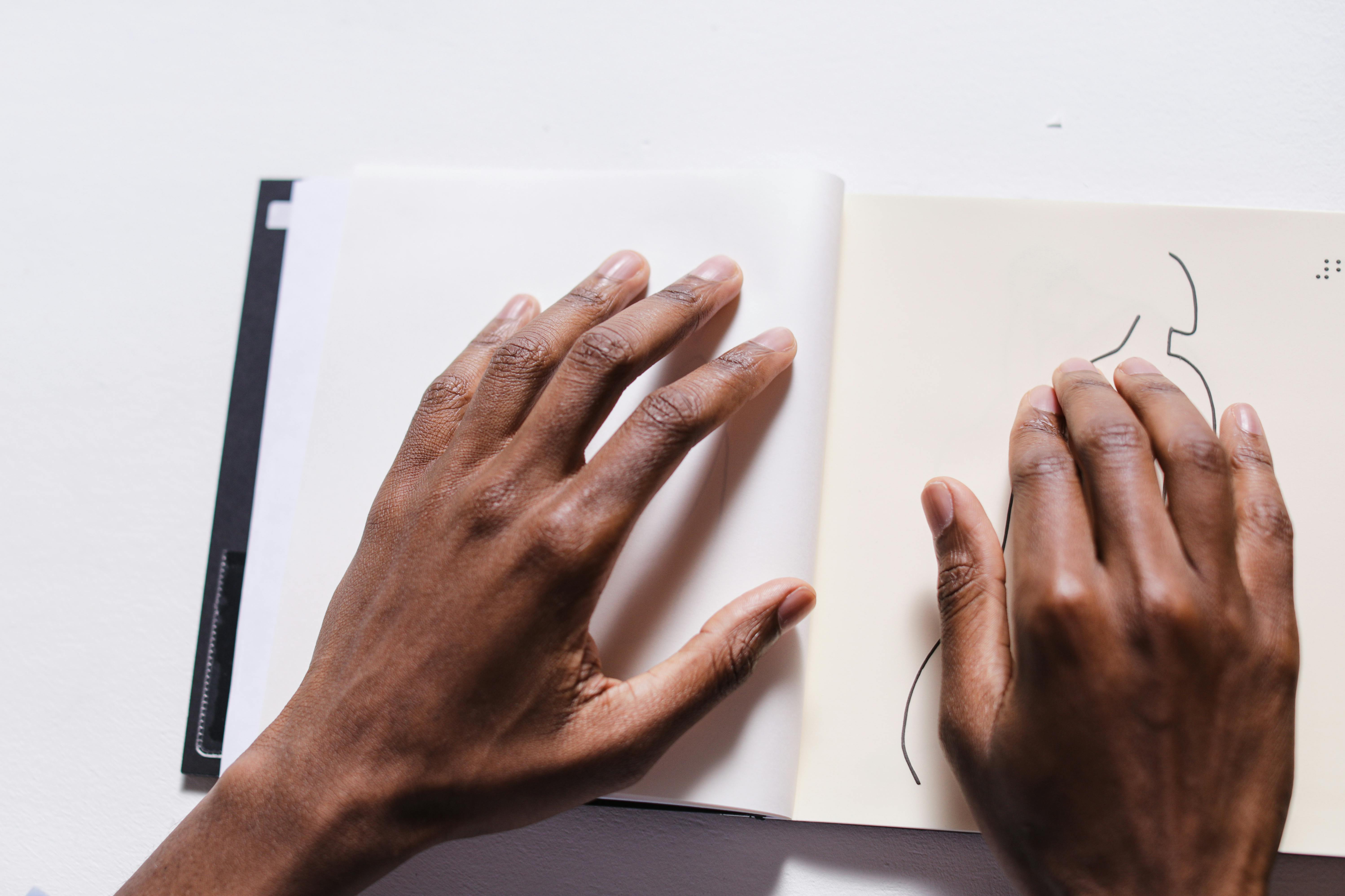 A Person's Hands on White Book · Free Stock Photo