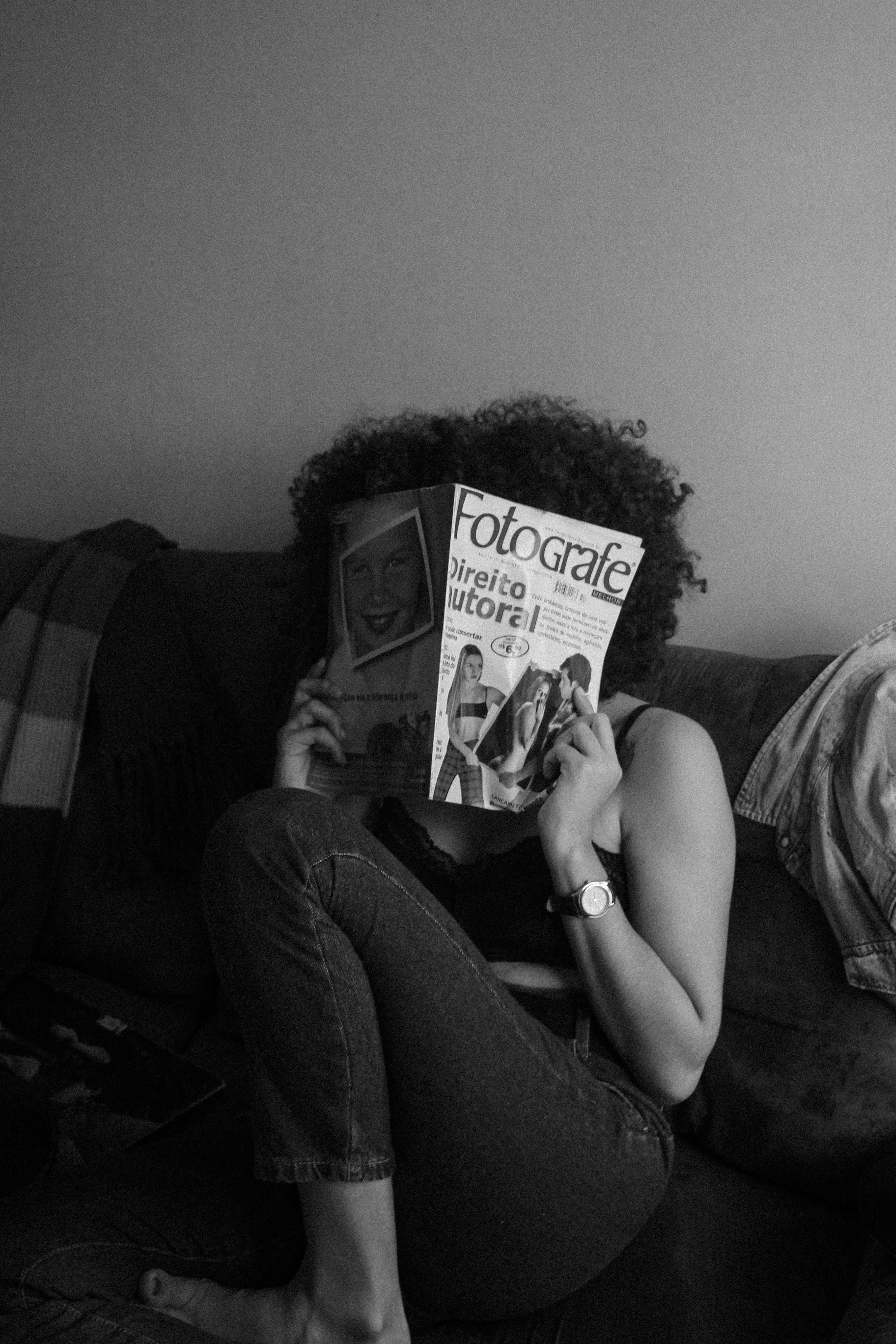 A Grayscale of a Woman Covering Her Face with a Magazine · Free Stock Photo