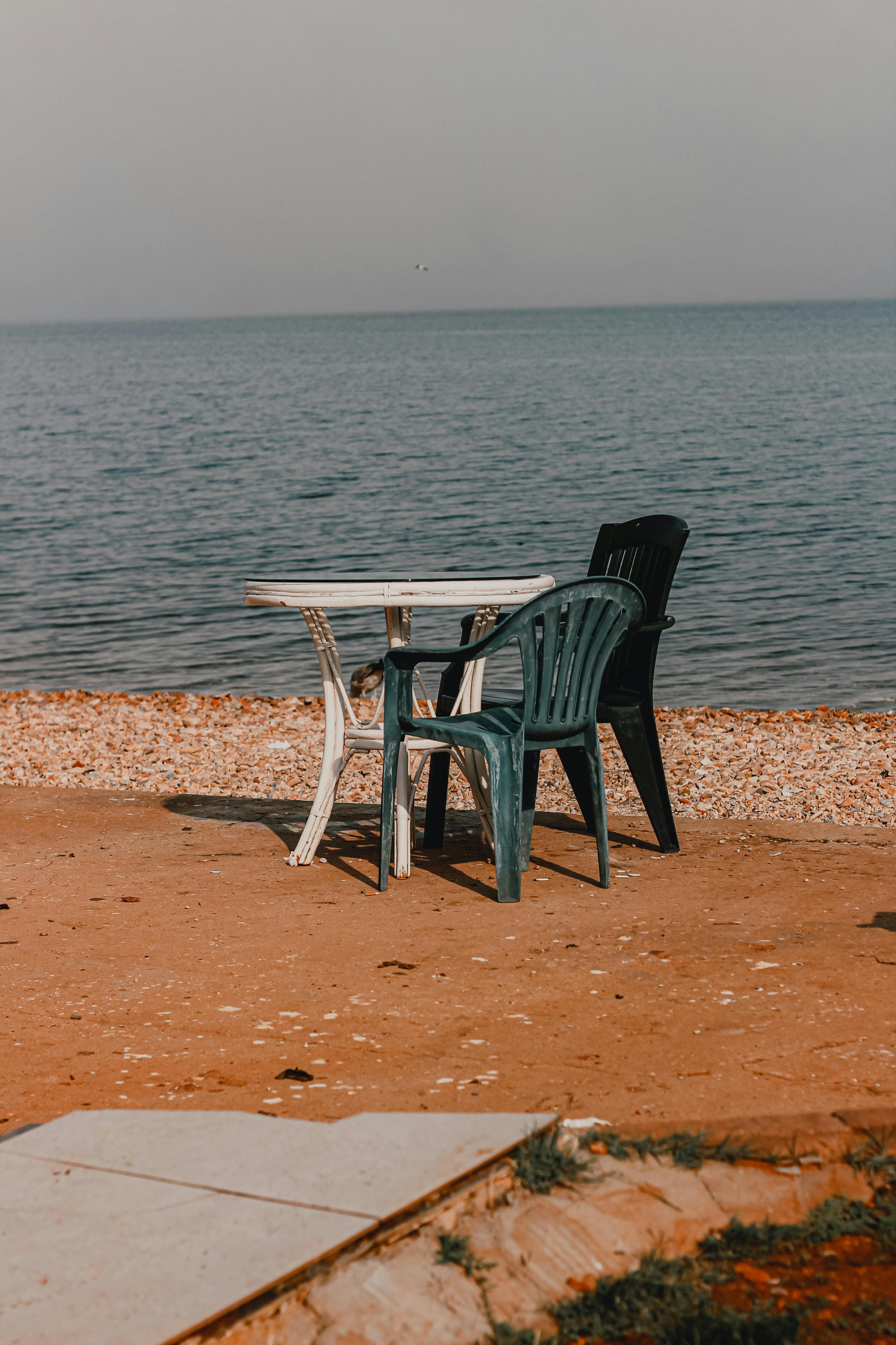 Table and Chairs on a Seashore · Free Stock Photo