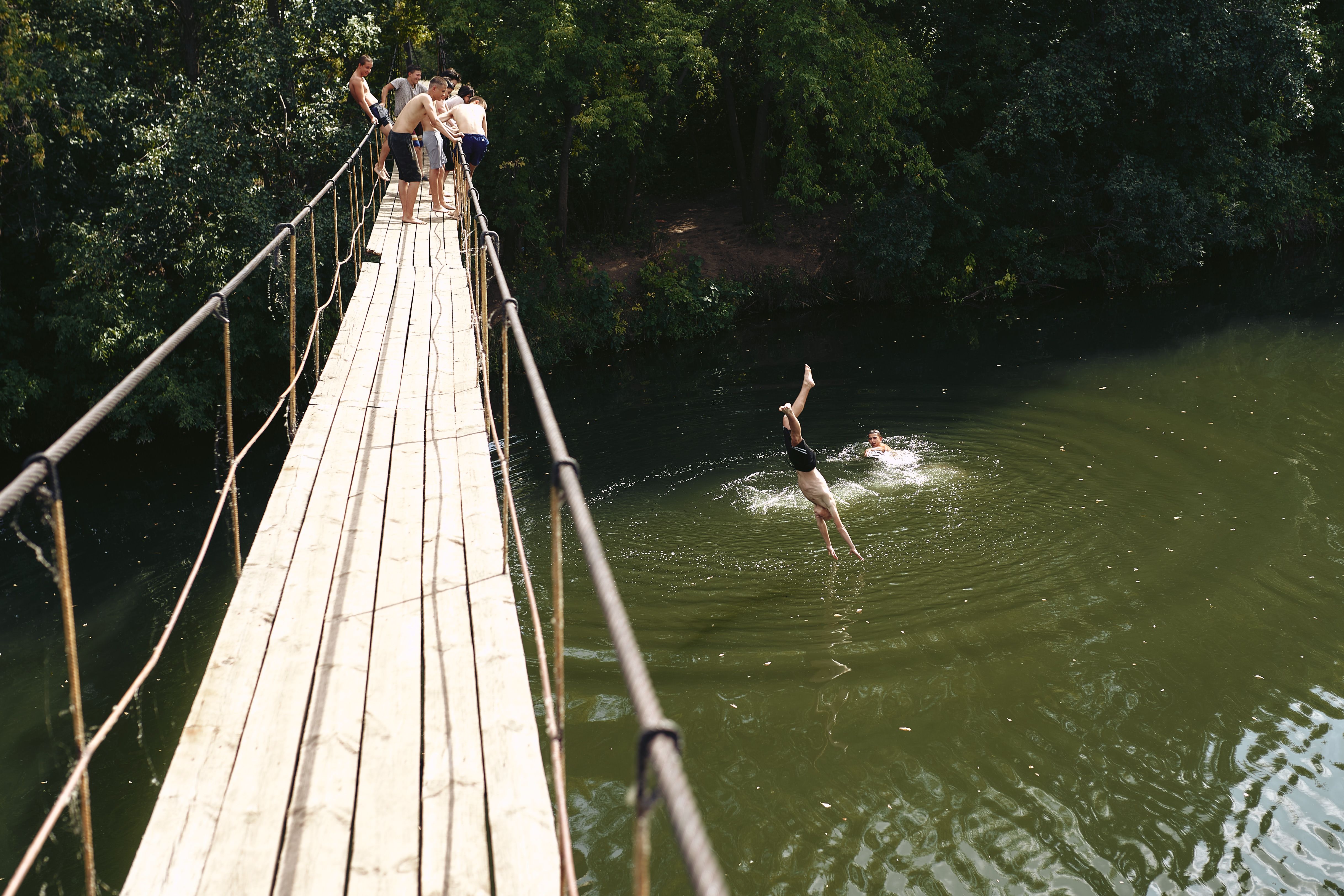 A Man Diving on a River from a Footbridge · Free Stock Photo