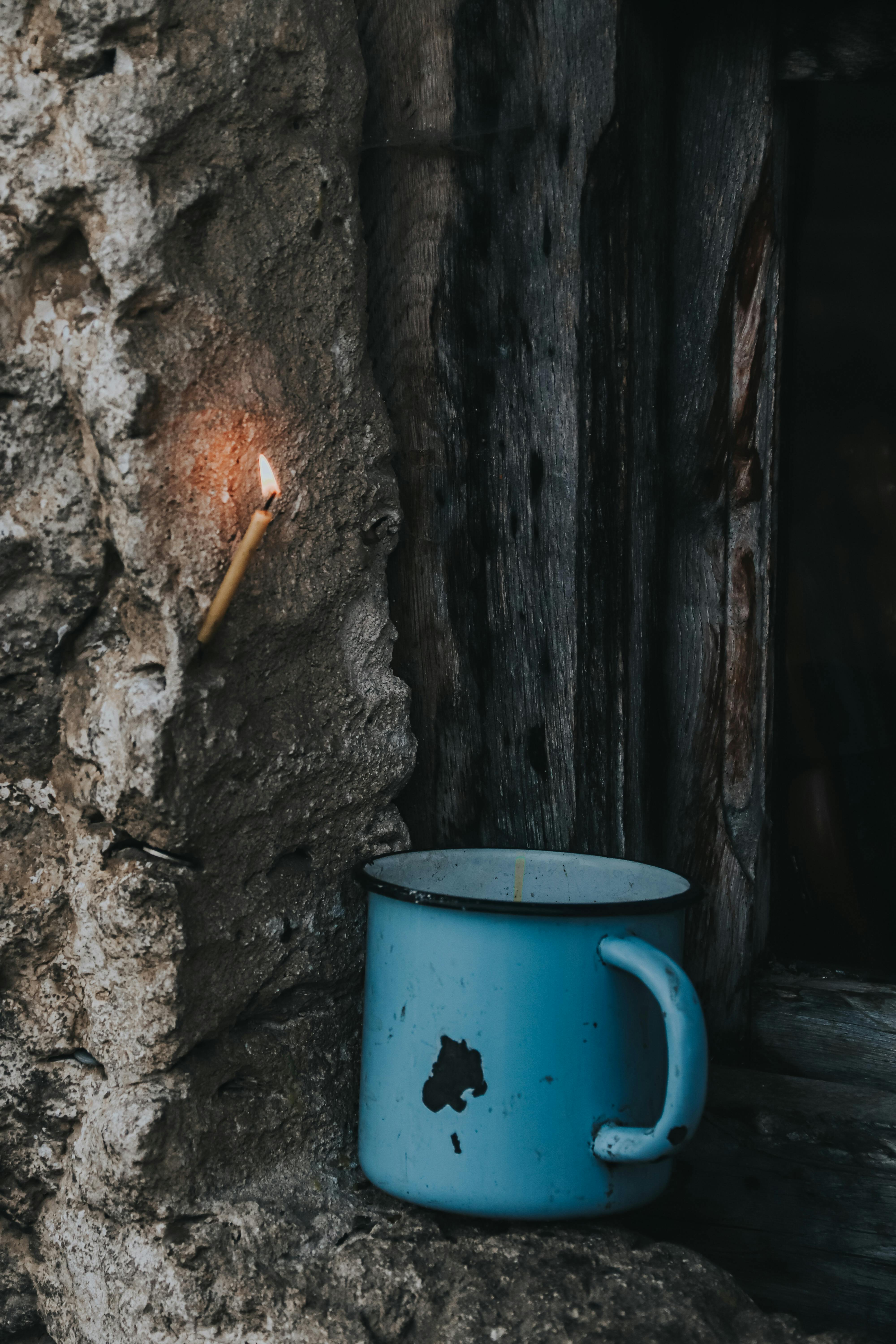 A Lighted Candle on a Wooden Chopping Board Beside a Mug with Cream ...