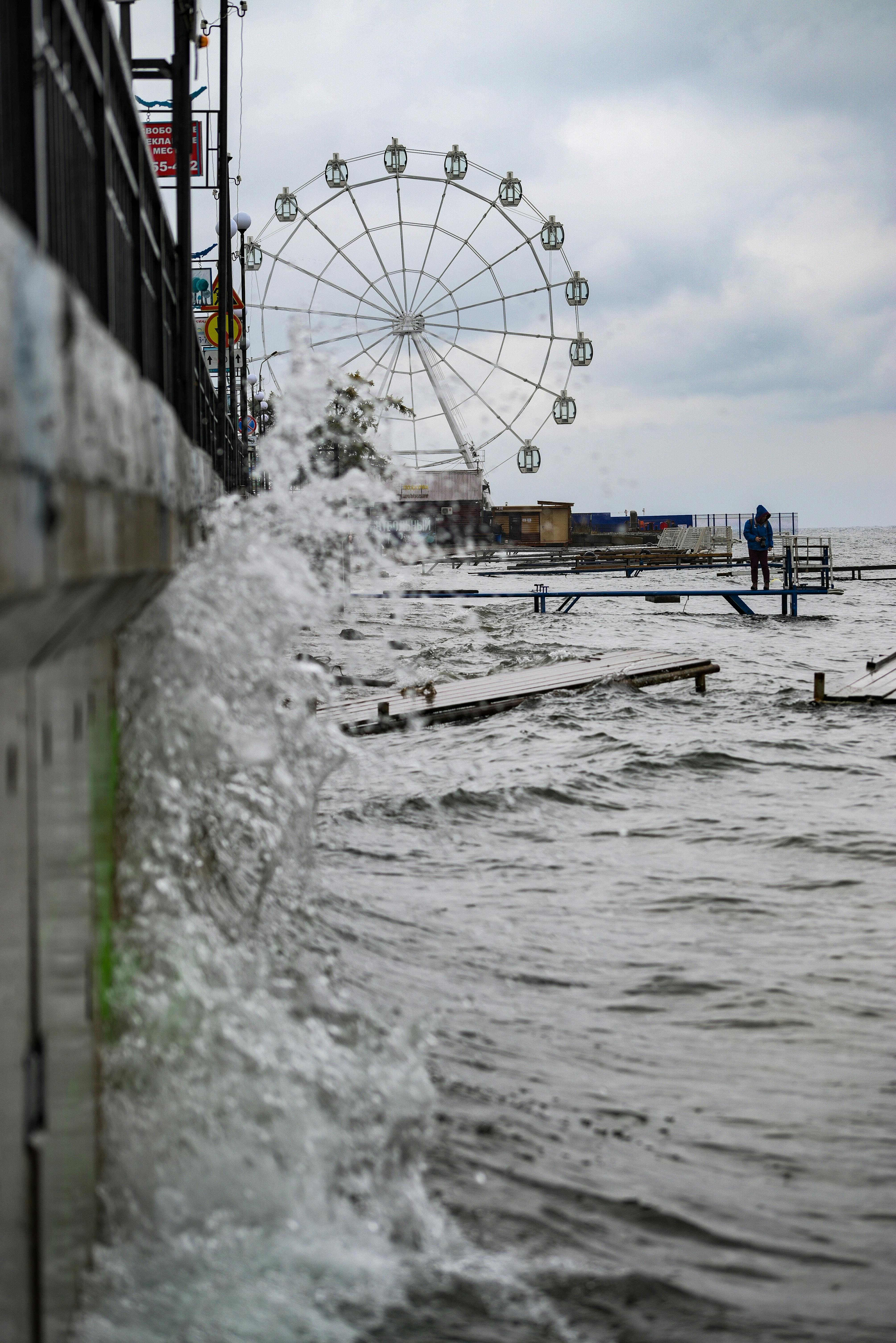 Wave Hitting Wall and Ferris Wheel in Background · Free Stock Photo