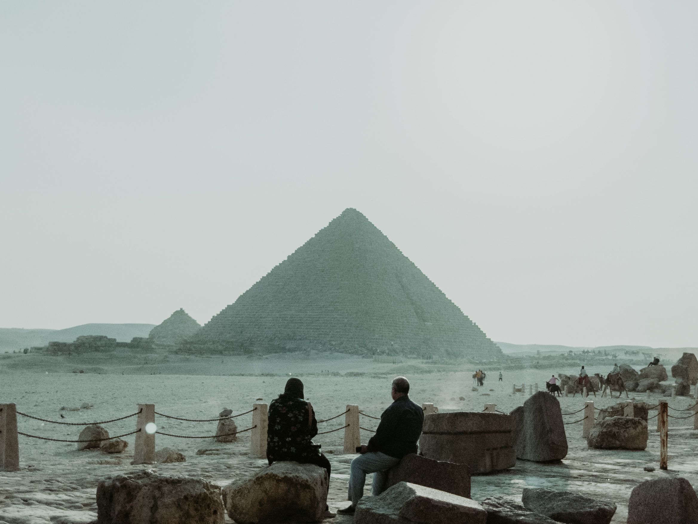 A Couple Sitting on Rocks while Looking at a Pyramid · Free Stock Photo