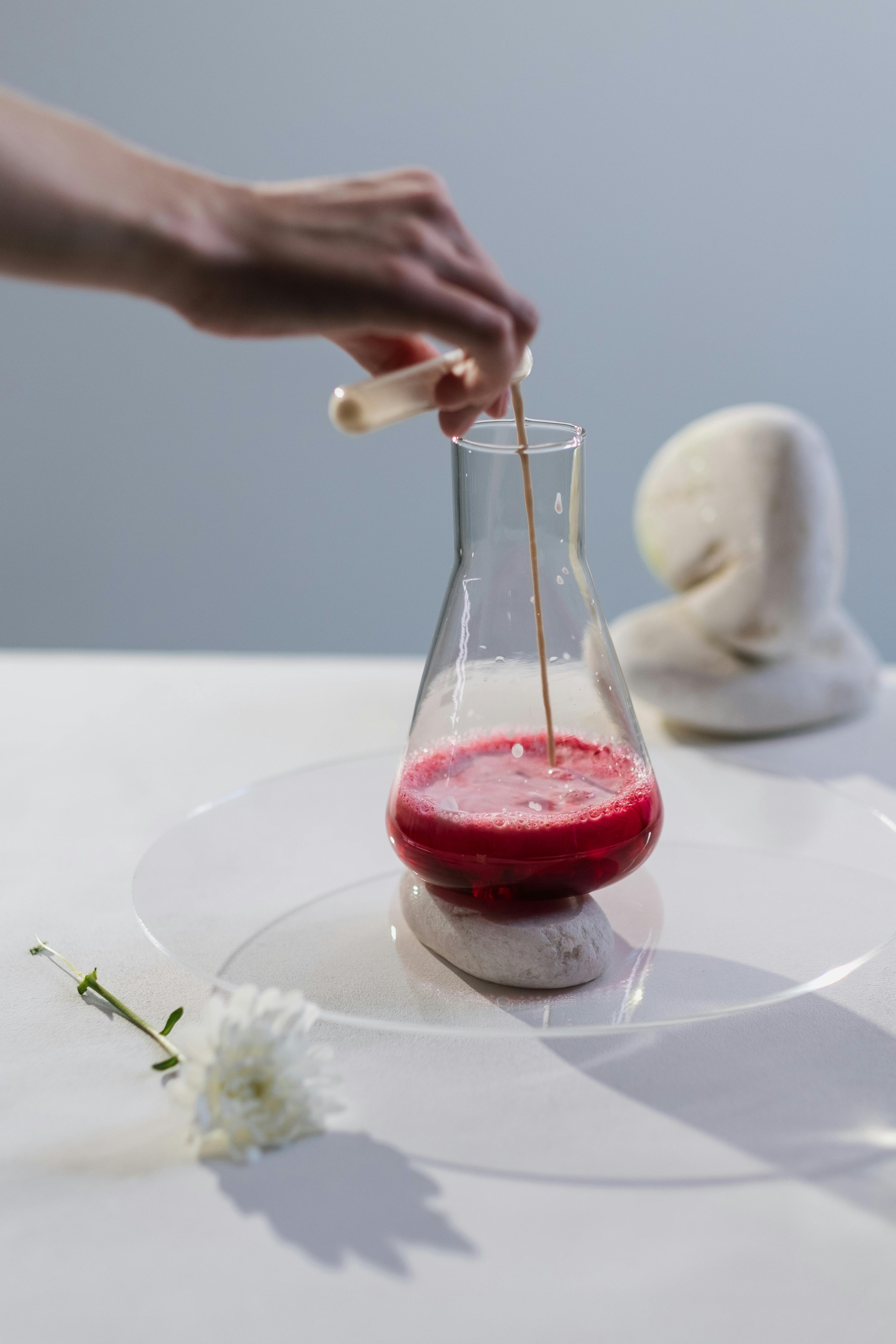 A Hand Pouring a Liquid into Chemistry Flask · Free Stock Photo