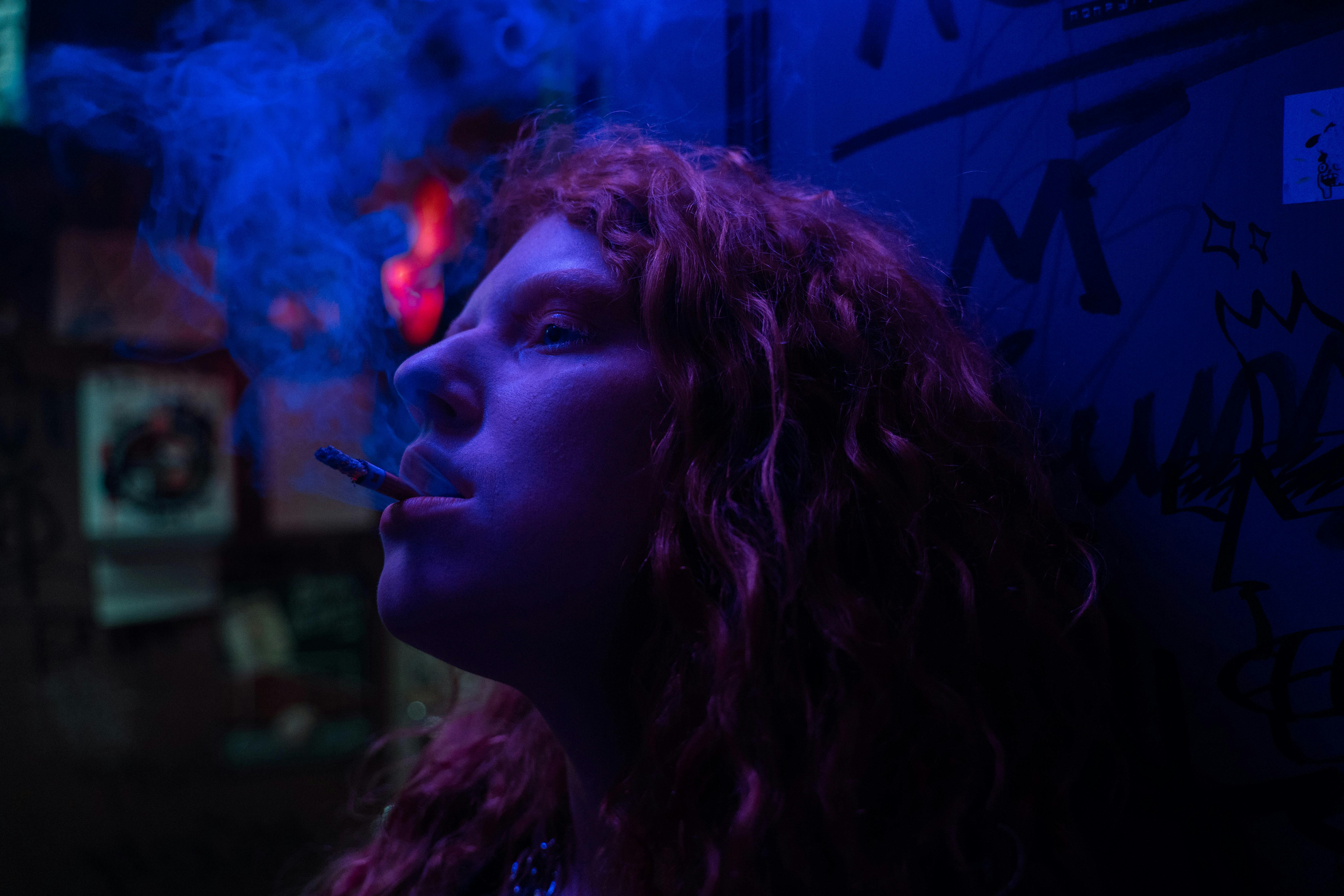 A Woman with Red Curly Hair Smoking a Cigarette · Free Stock Photo