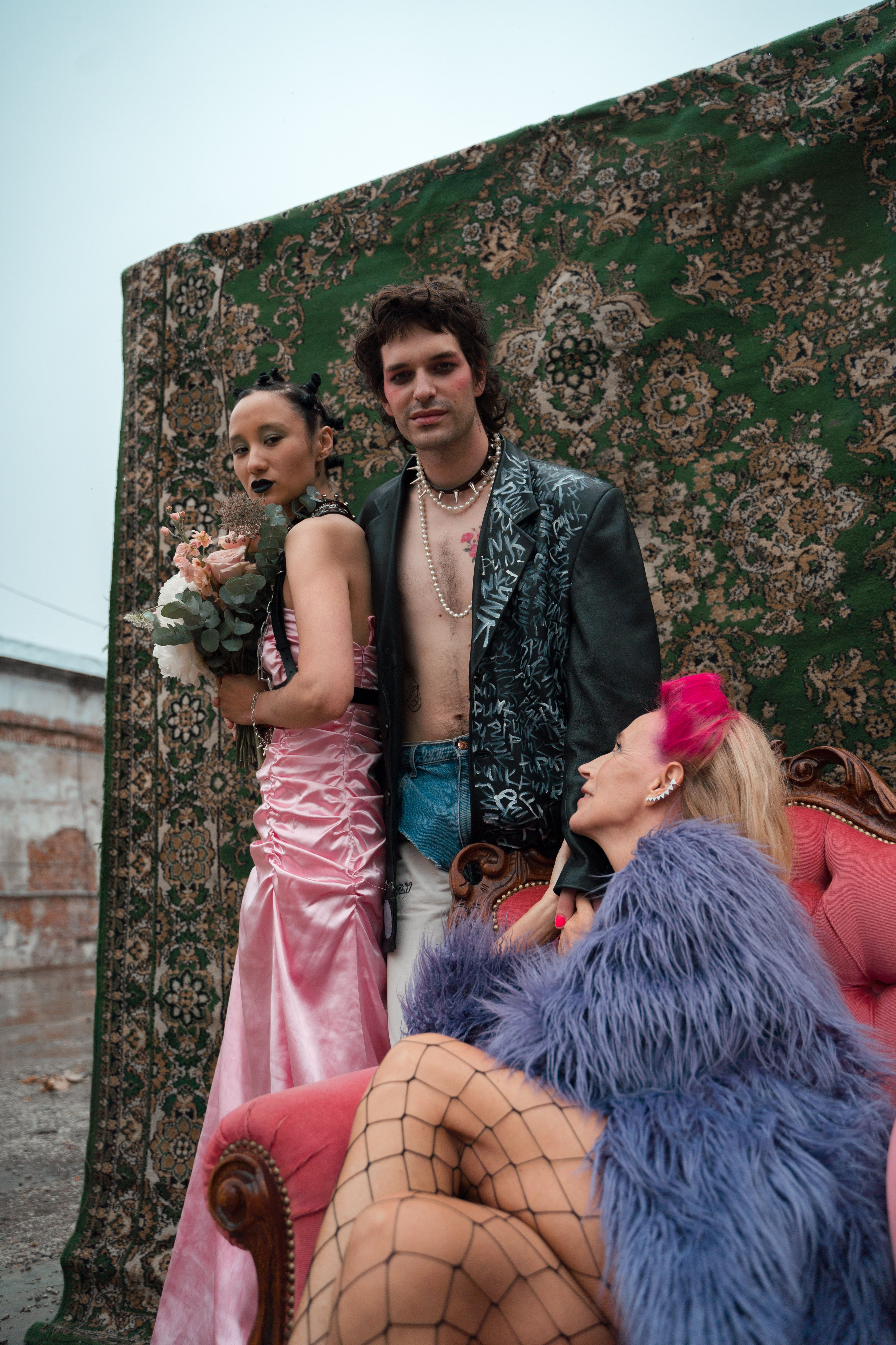 Group of People in Punk Costumes Posing against a Patterned Rug Hanging ...