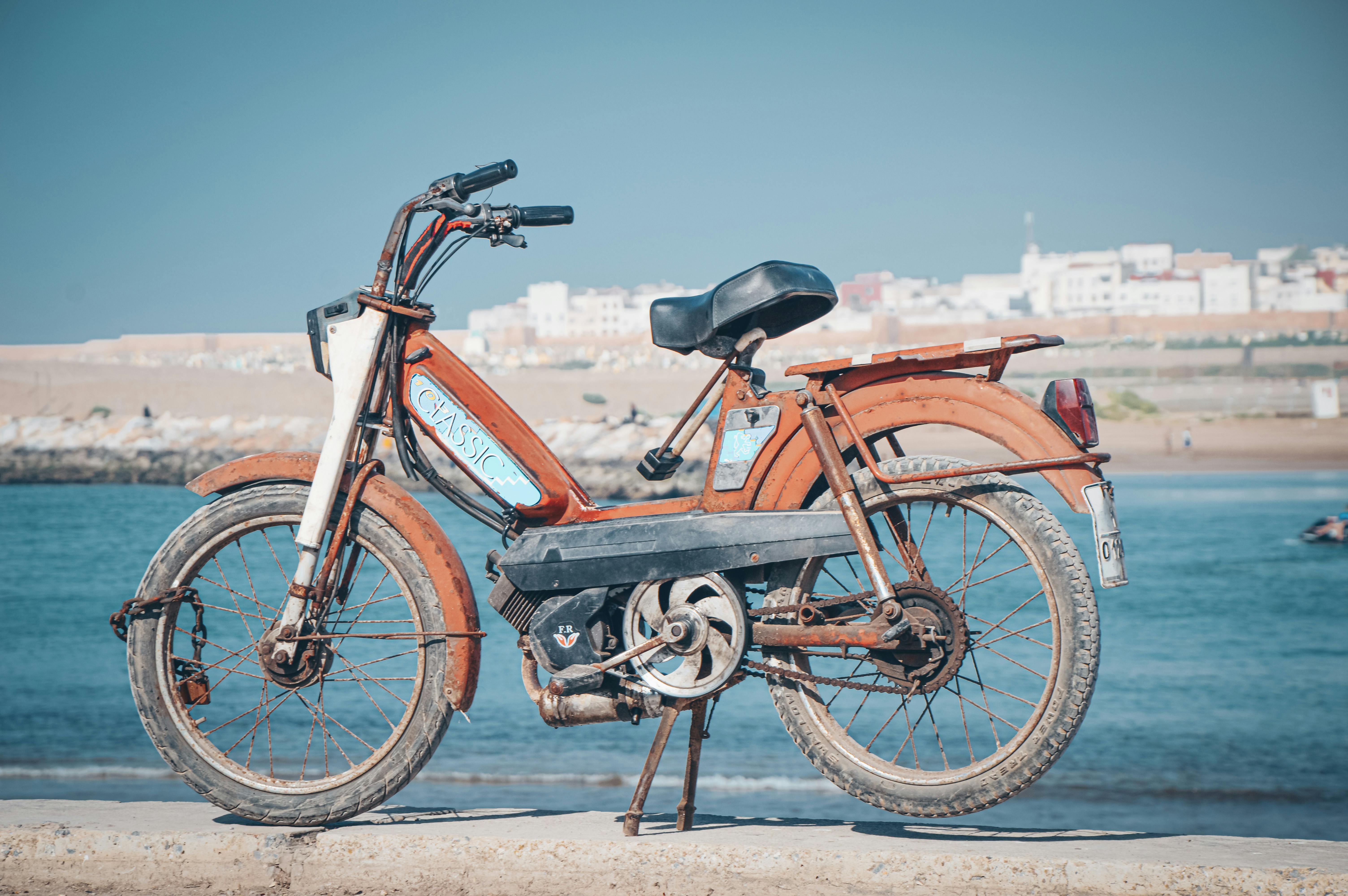 Orange Moped Parked Near a Sea · Free Stock Photo