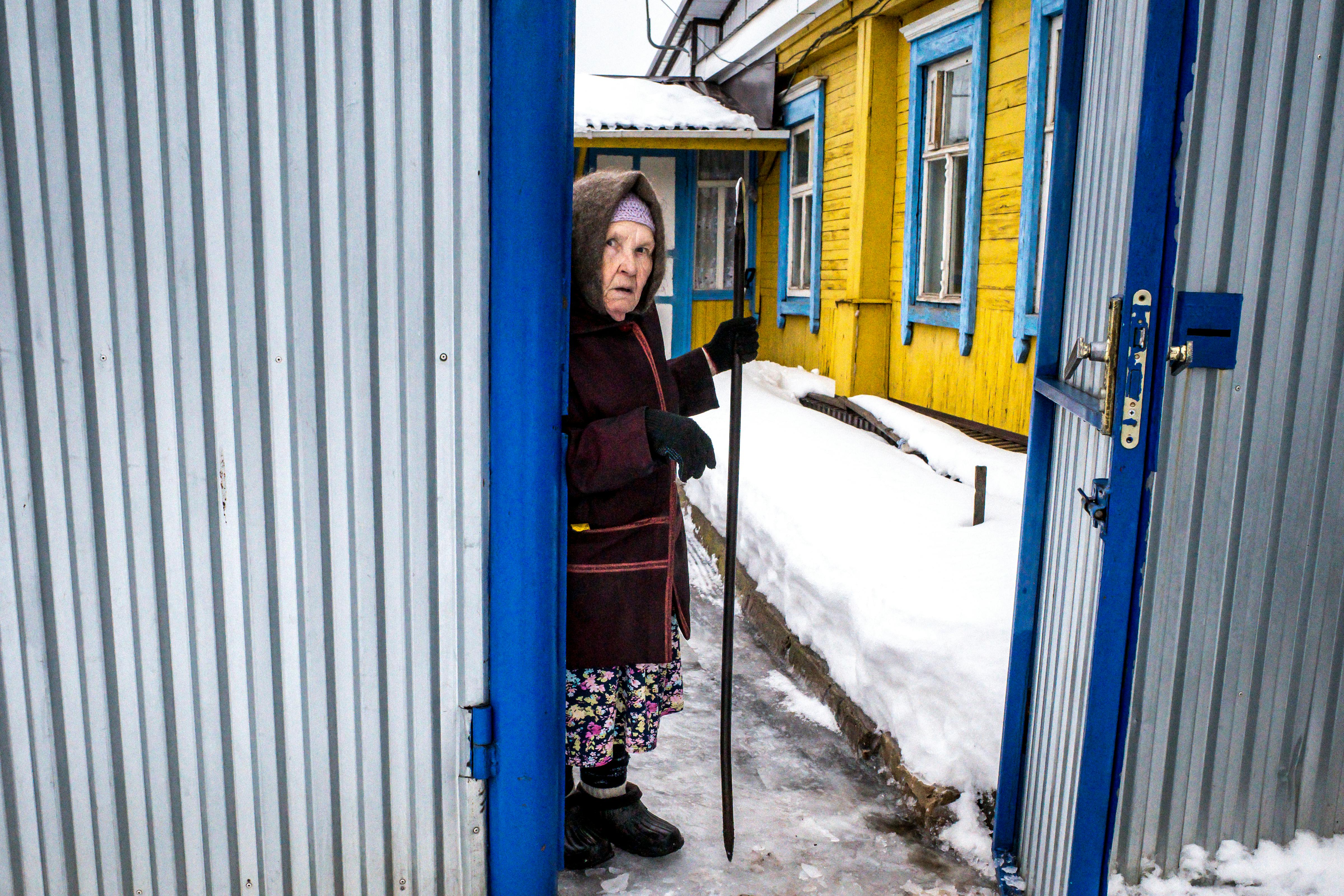 Elderly Woman Standing Beside a Gate · Free Stock Photo