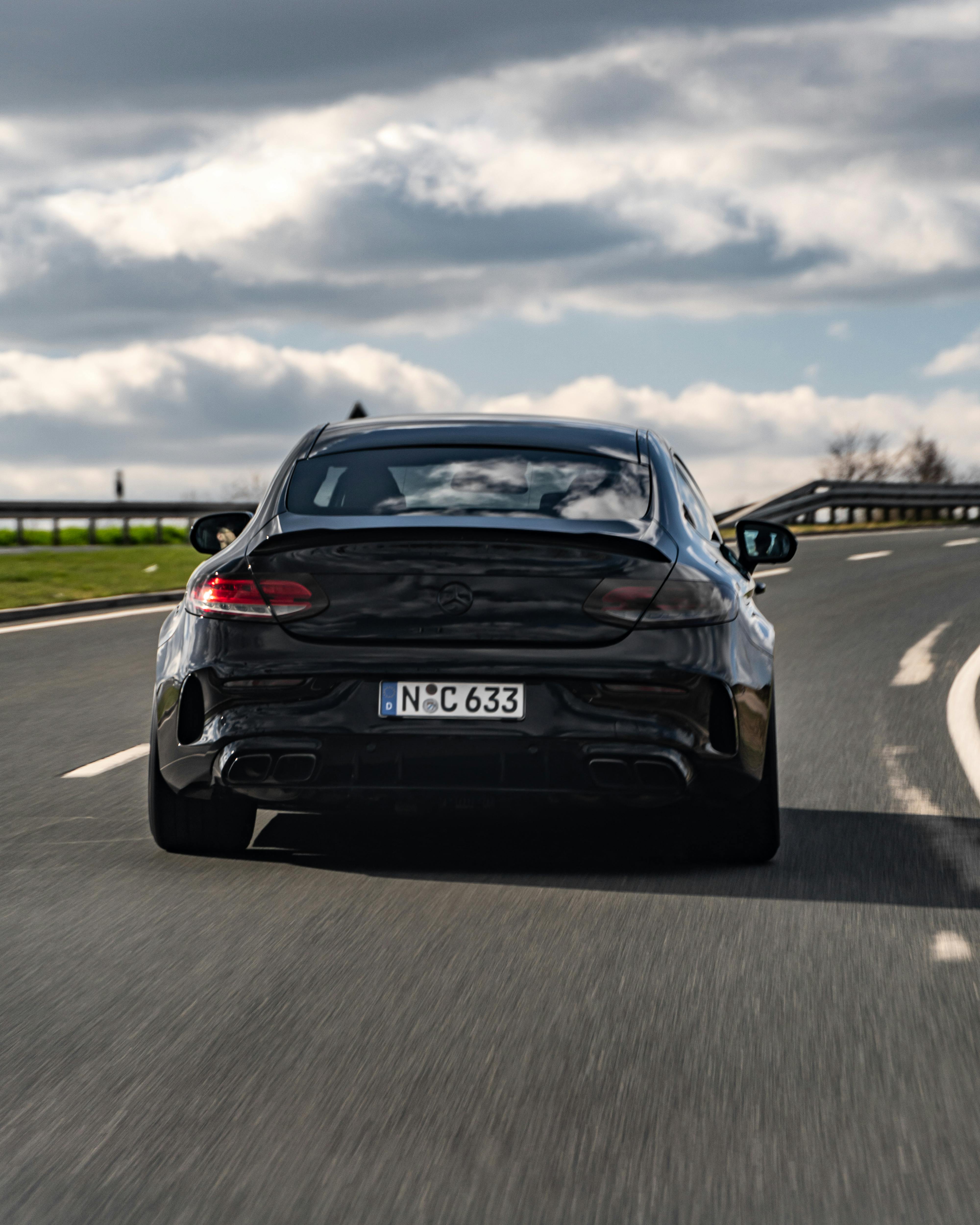 A Black Mercedes Benz Driving on the Road · Free Stock Photo