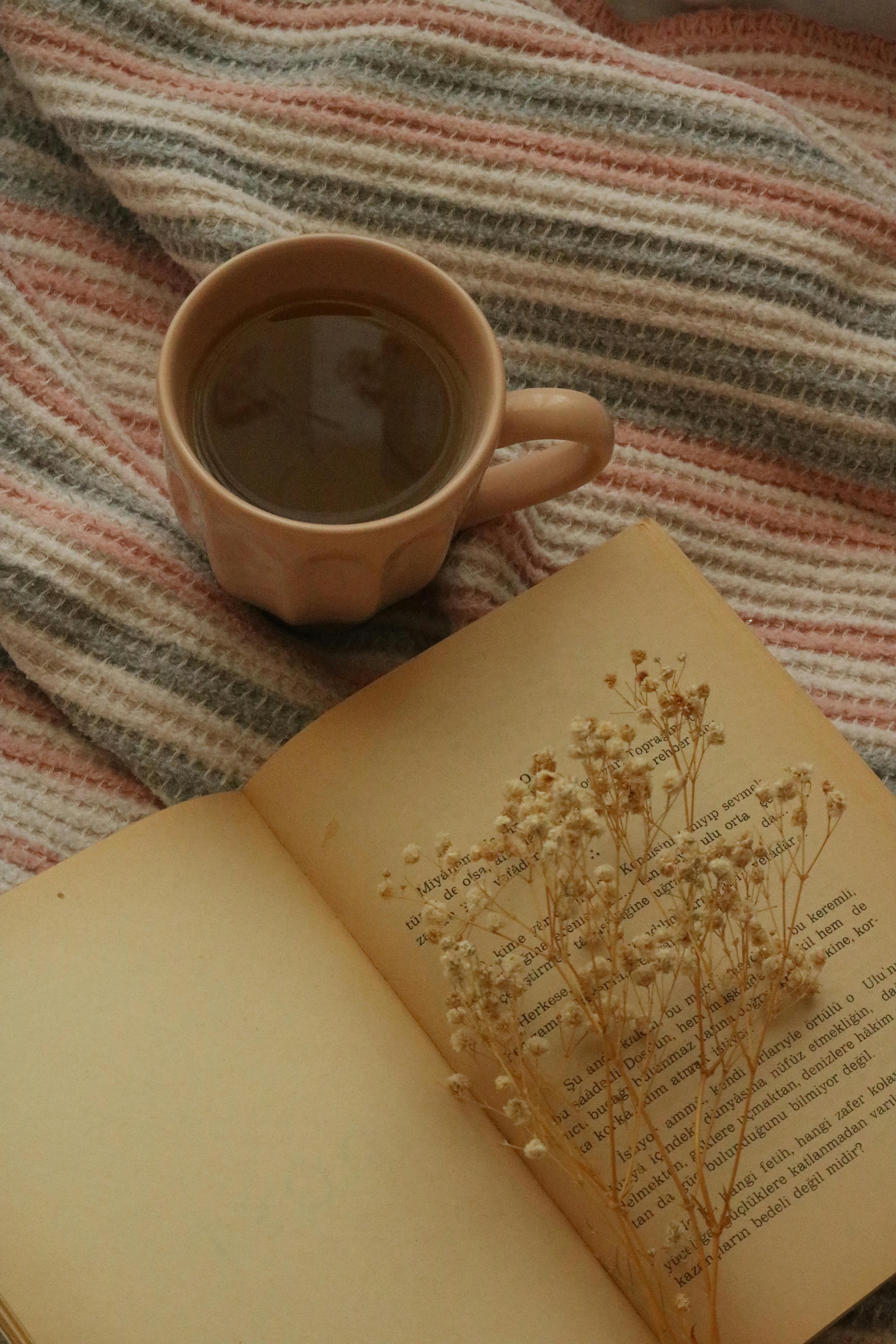 A Mug with Hot Drink Beside an Open Book with White Flowers · Free ...