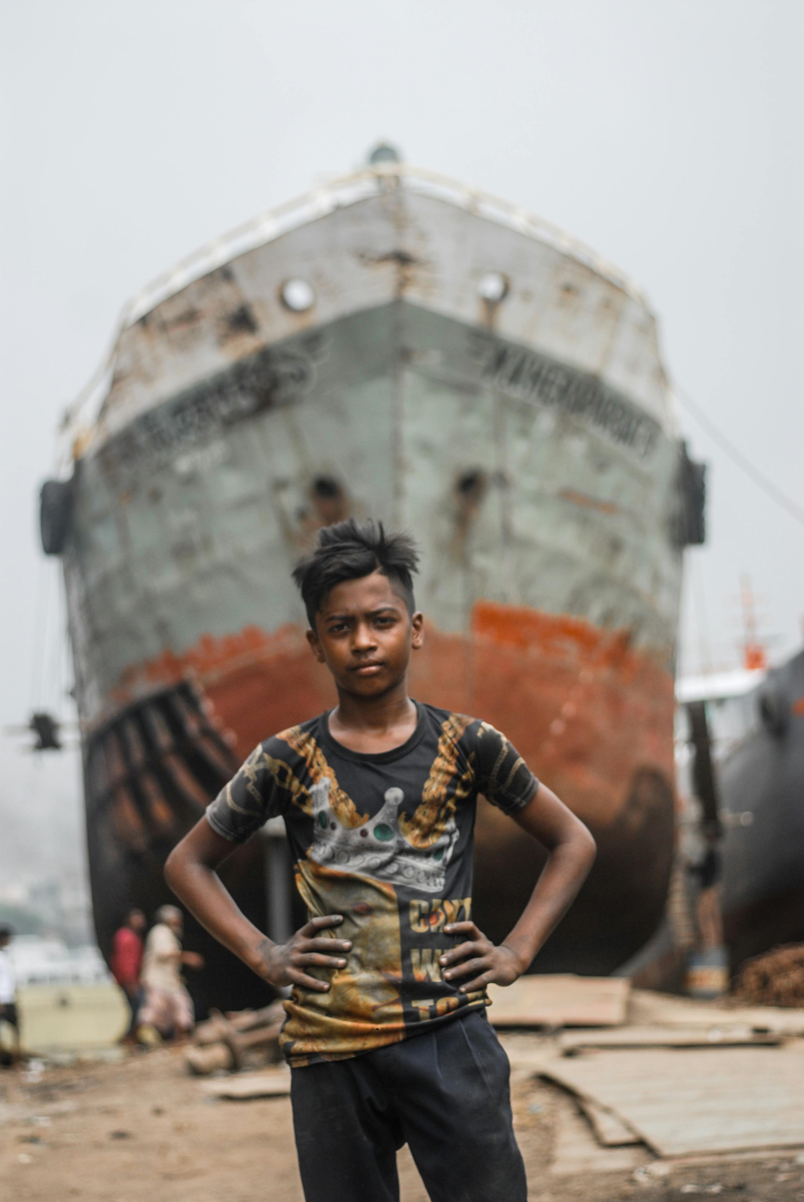 A Boy Standing in Front of an Abandoned Ship · Free Stock Photo