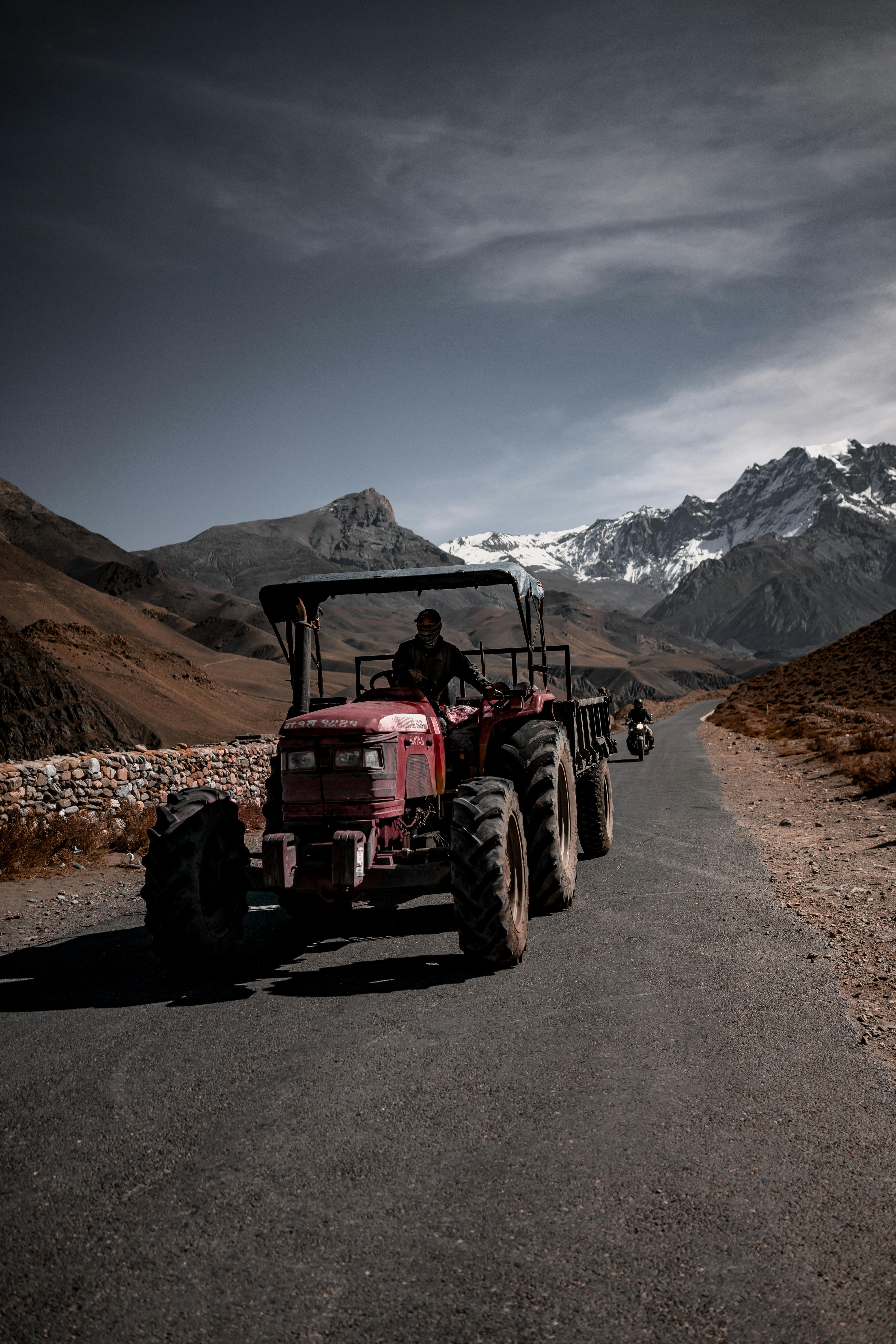 Man Driving a Red Tractor on the Road · Free Stock Photo