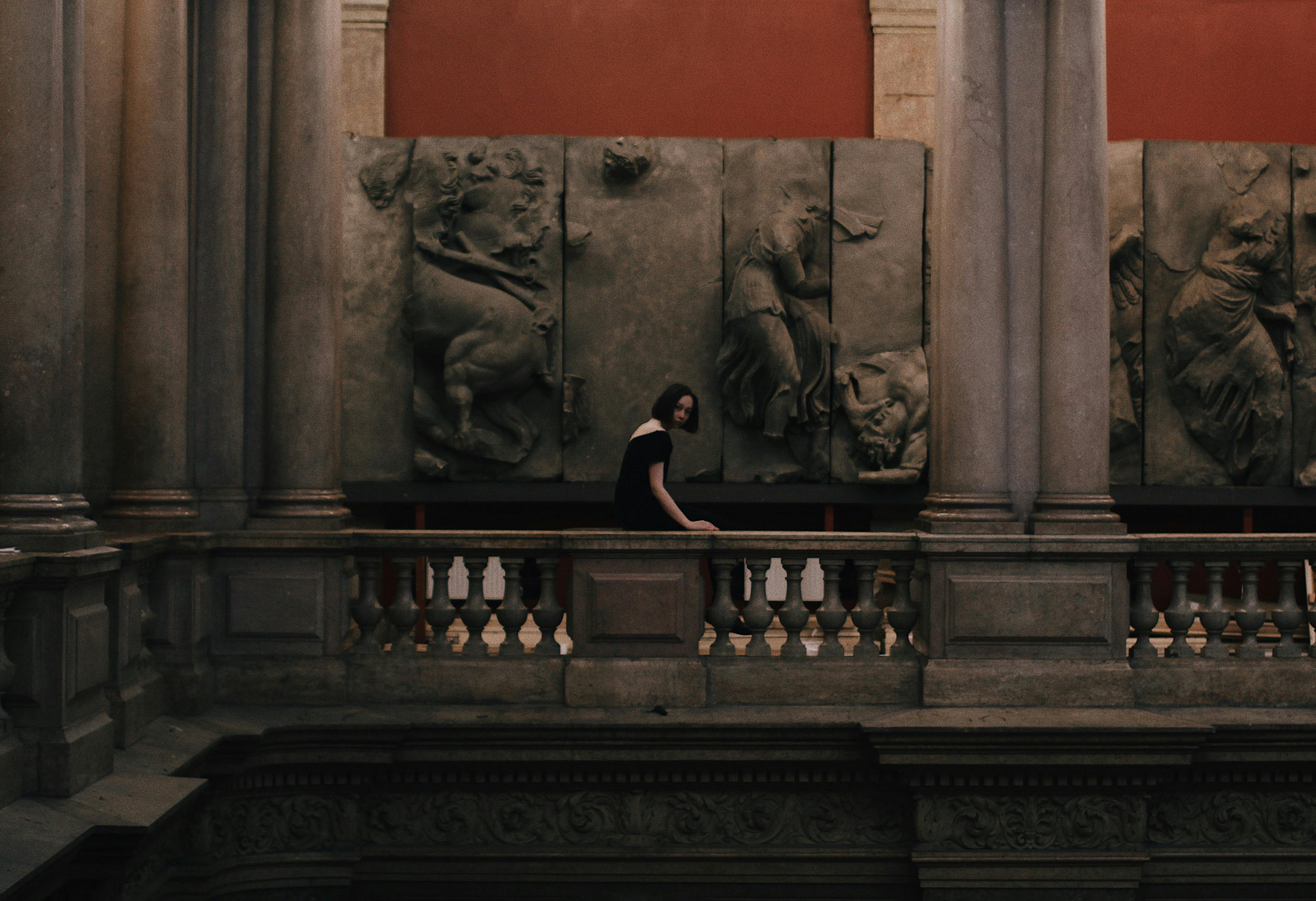 Woman Sitting in a Museum Behind a Dying Gaul Sculpture · Free Stock Photo