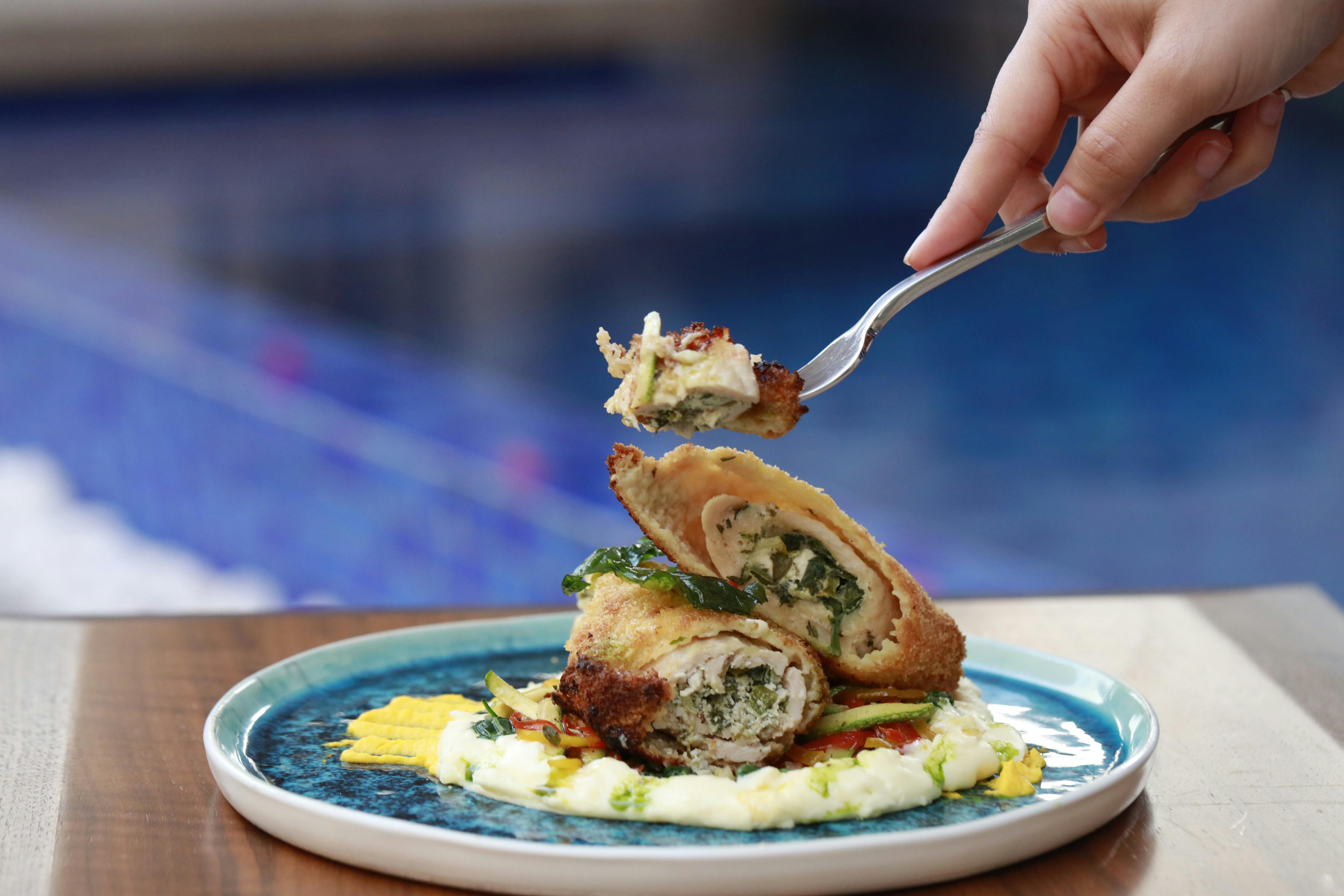 A Person Eating a Delicious Breaded Food in a Blue Plate · Free Stock Photo