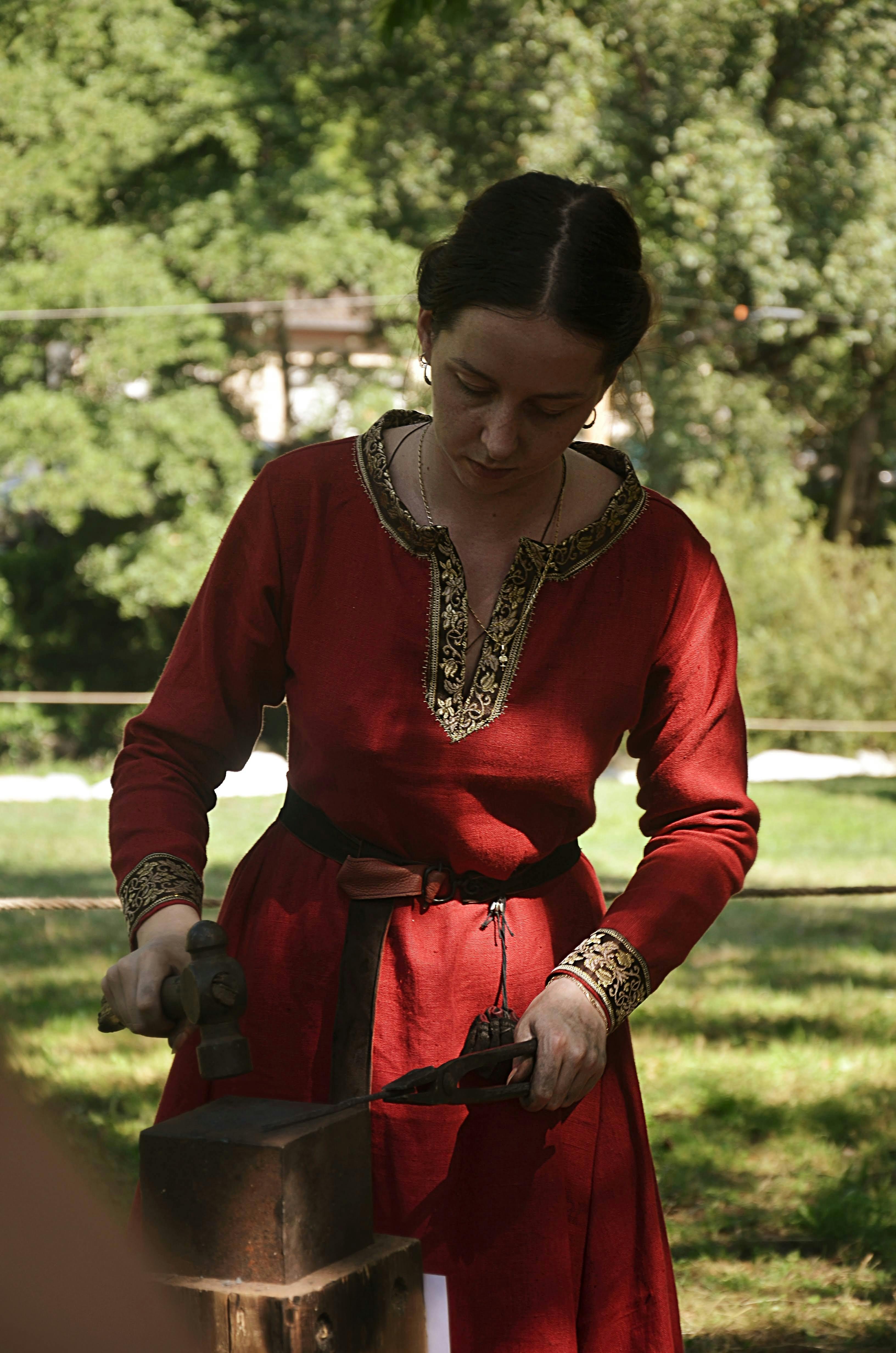 A Woman in Red Medieval Clothing Holding a Hammer and Pliers · Free ...