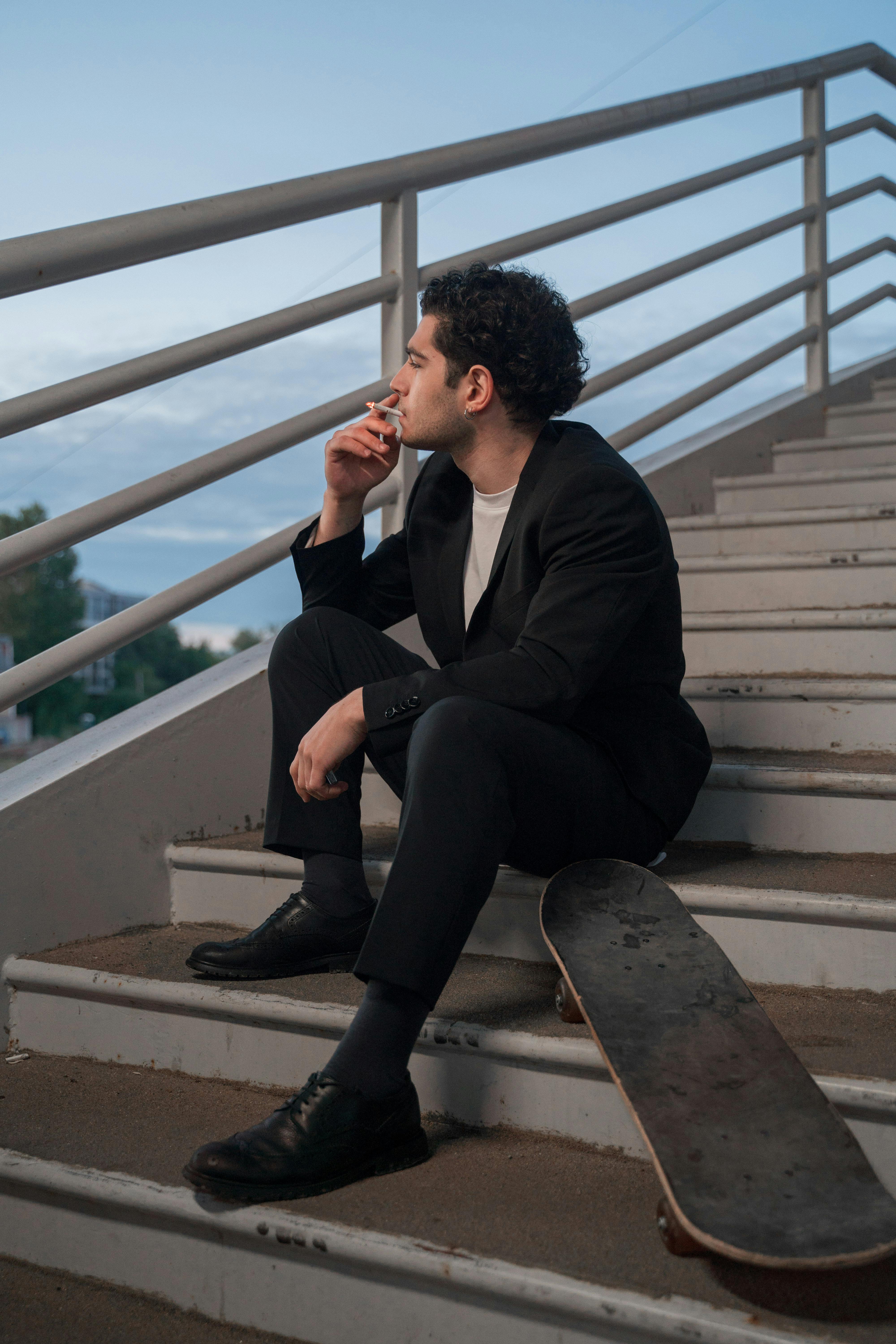 Man in Black Suit Smoking Cigarette on Stairs · Free Stock Photo