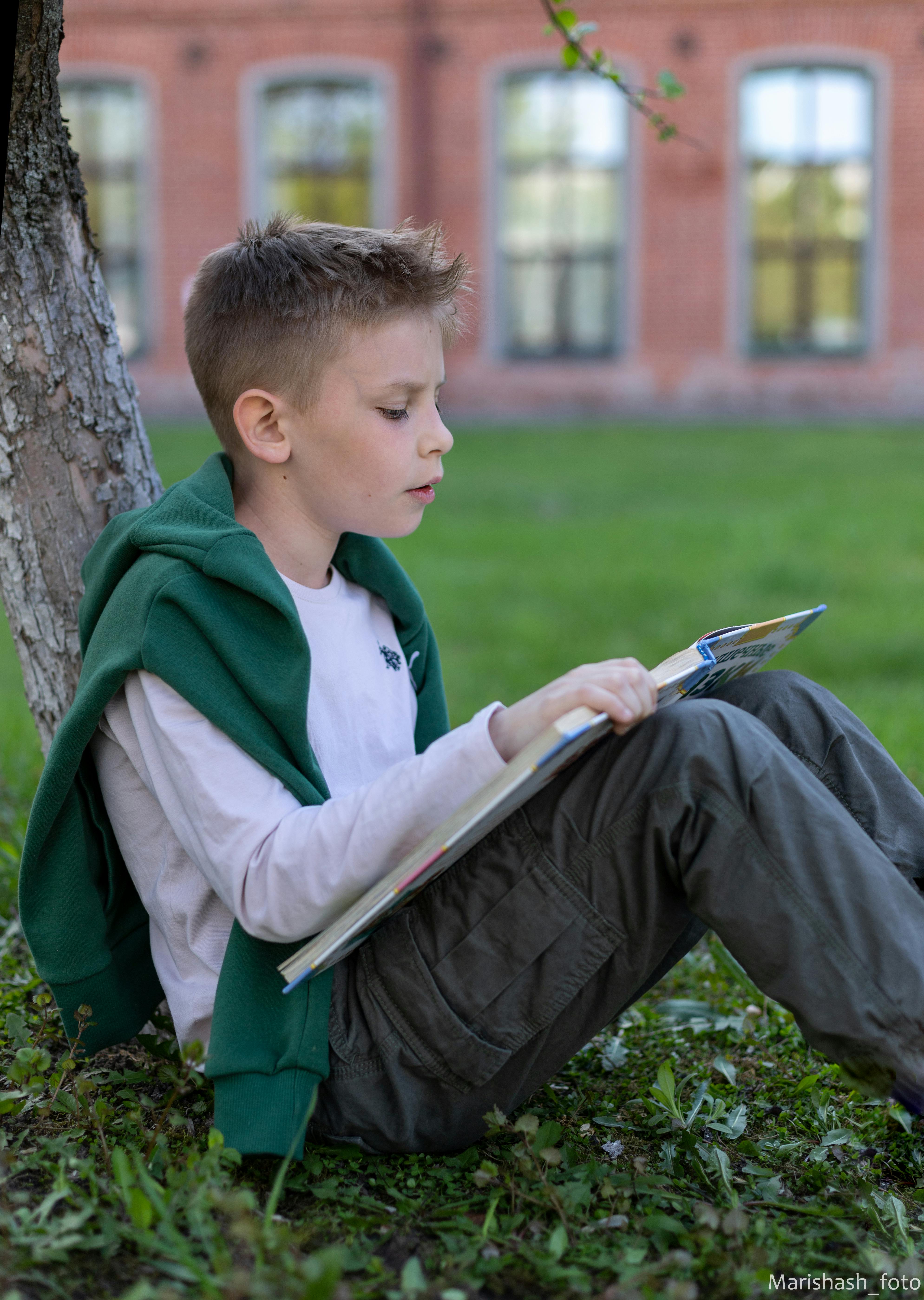 Boy Sitting on the Ground While Reading a Book · Free Stock Photo