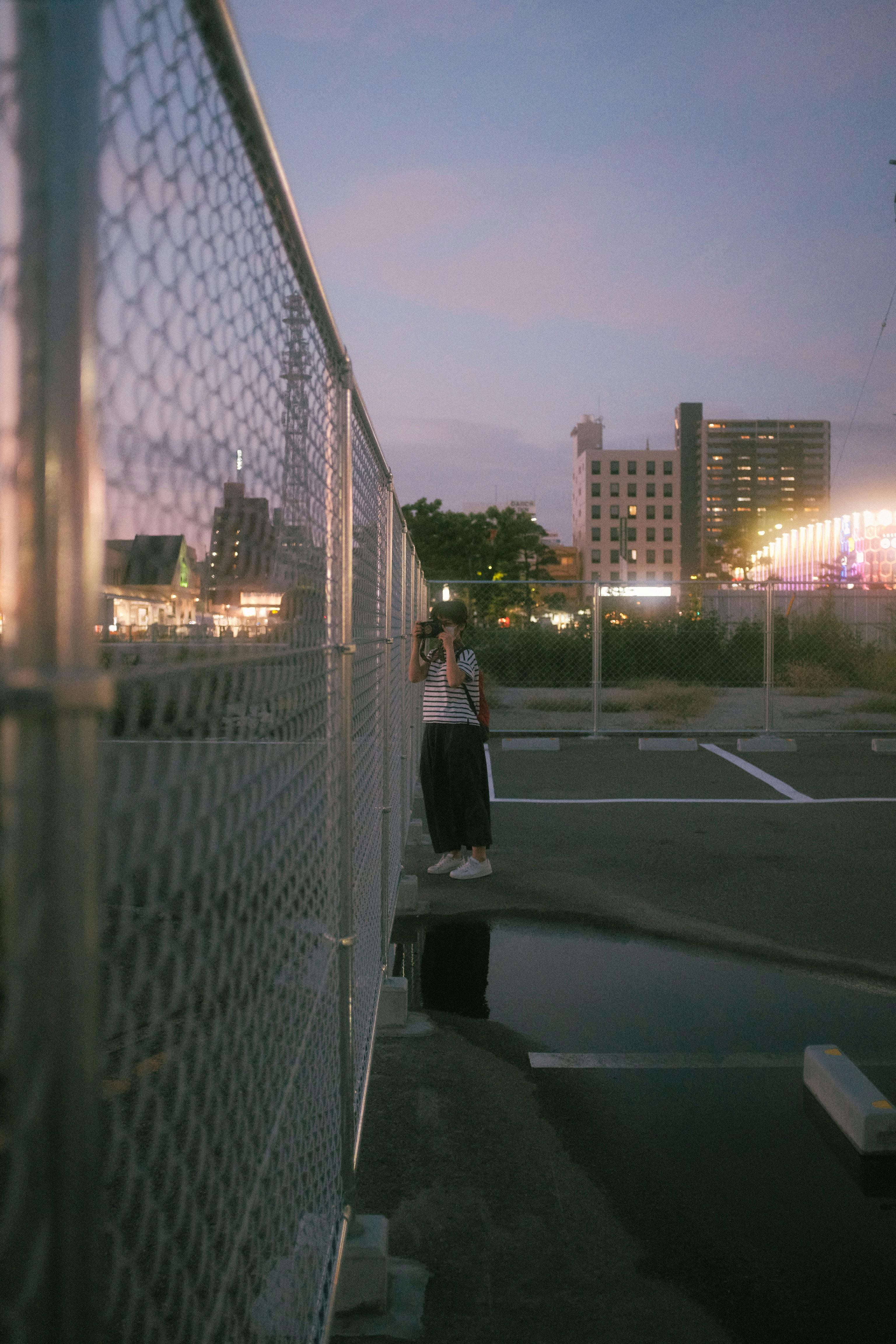 Woman in Red Checkered Shirt Holding on Fence · Free Stock Photo