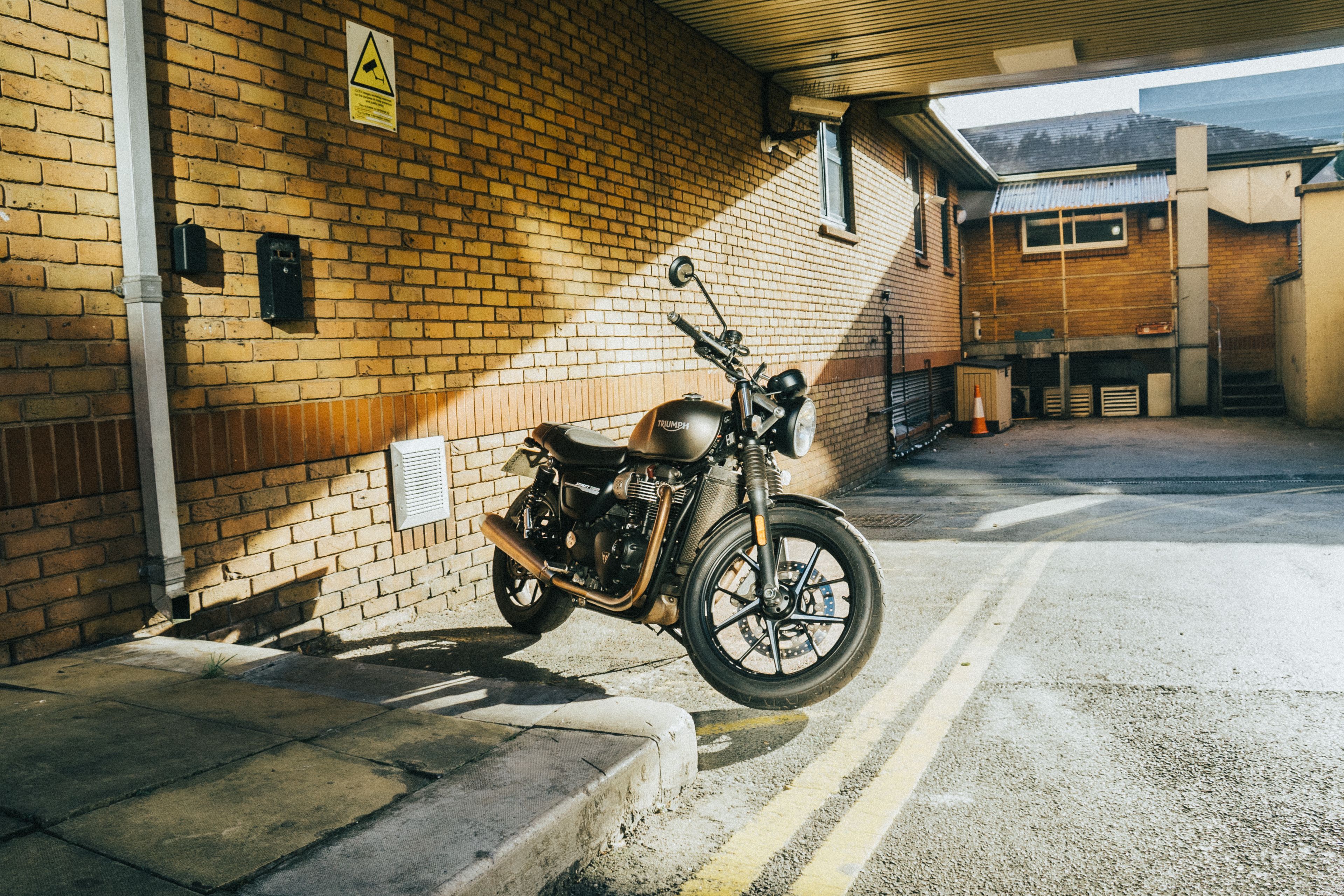 Black Motorcycle Standing by Brick Wall · Free Stock Photo