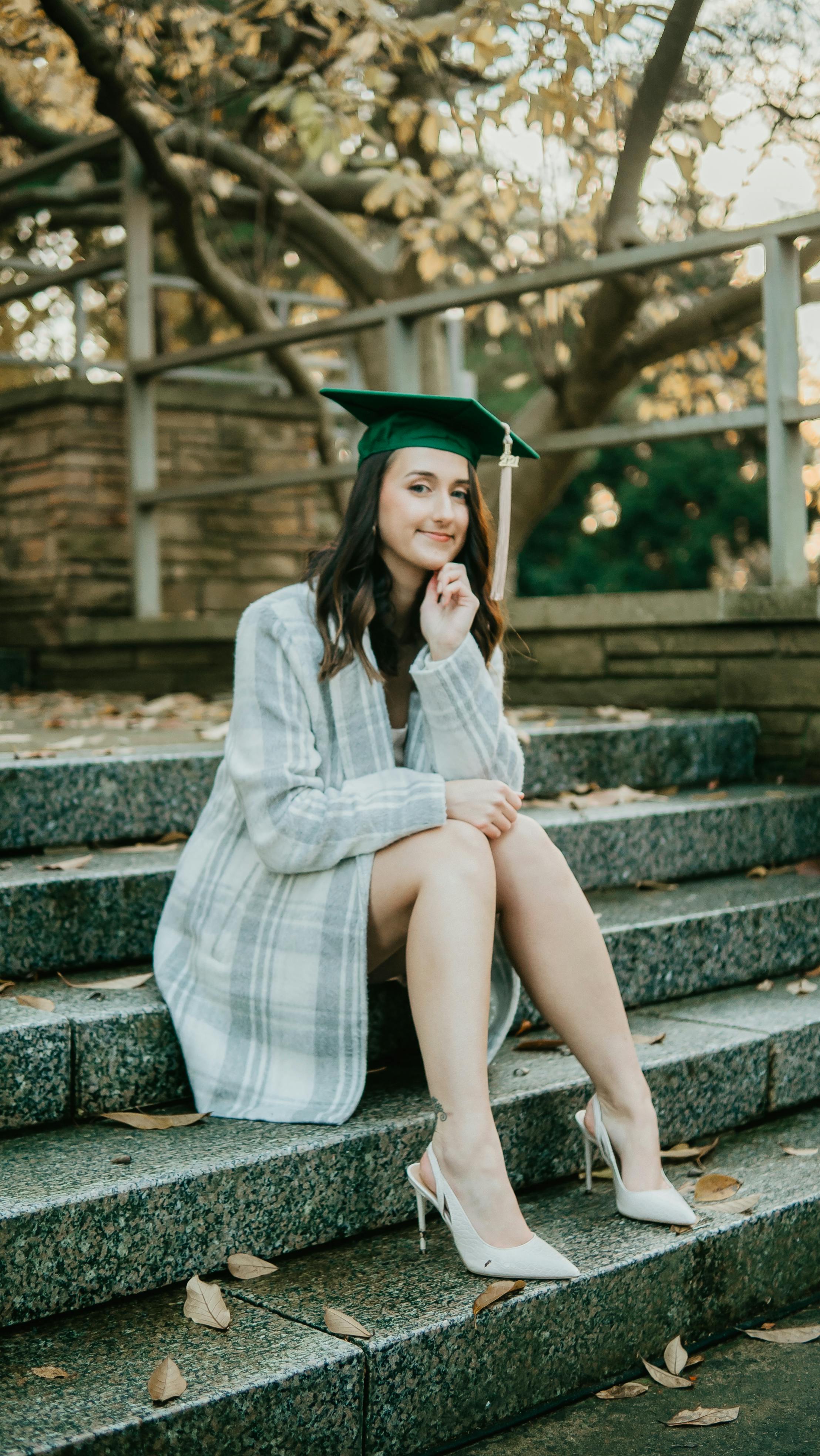 A Woman Sitting on the Stairway Wearing a Graduation Cap · Free Stock Photo