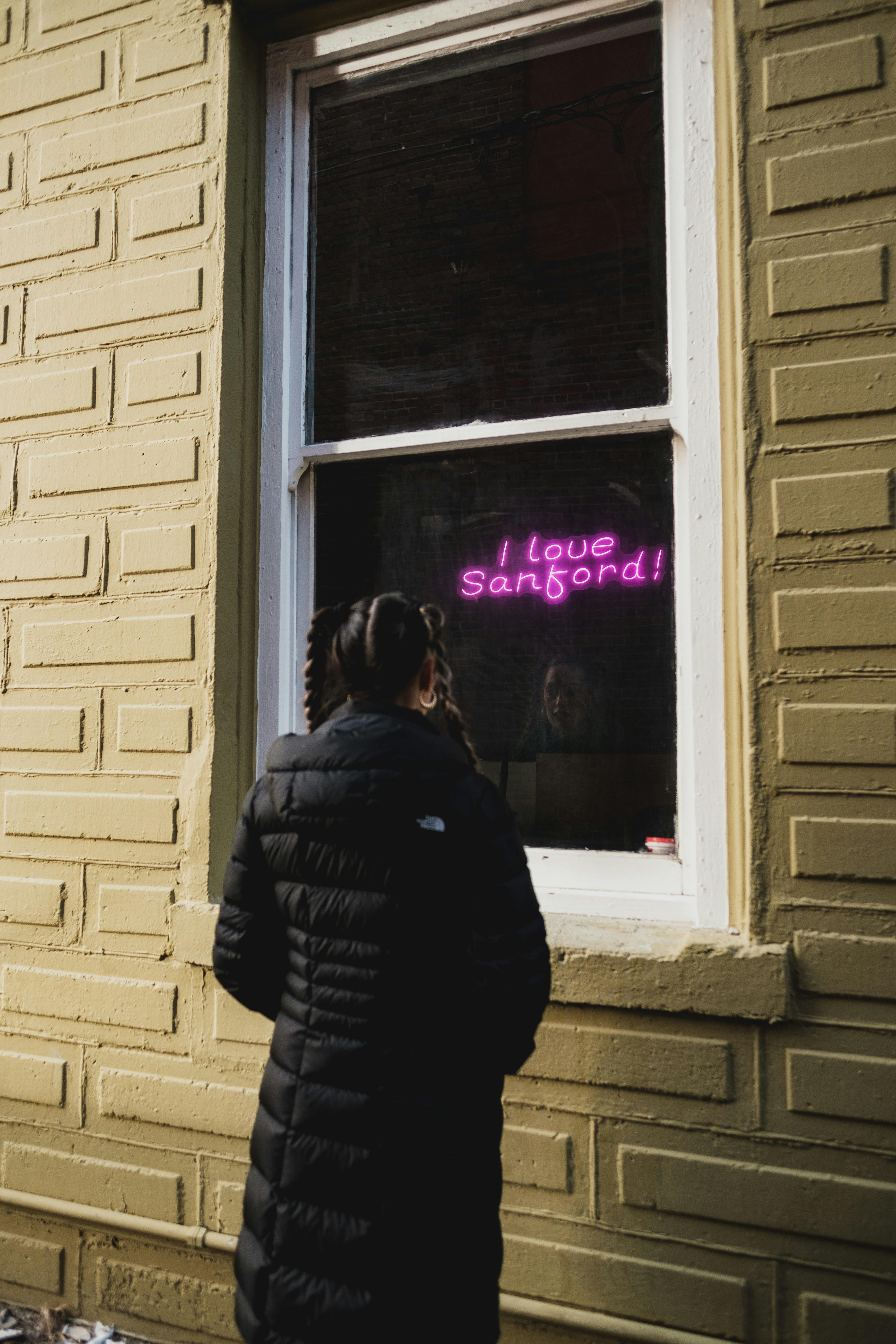 A Woman in Puffer Jacket Standing Near a Glass Window · Free Stock Photo
