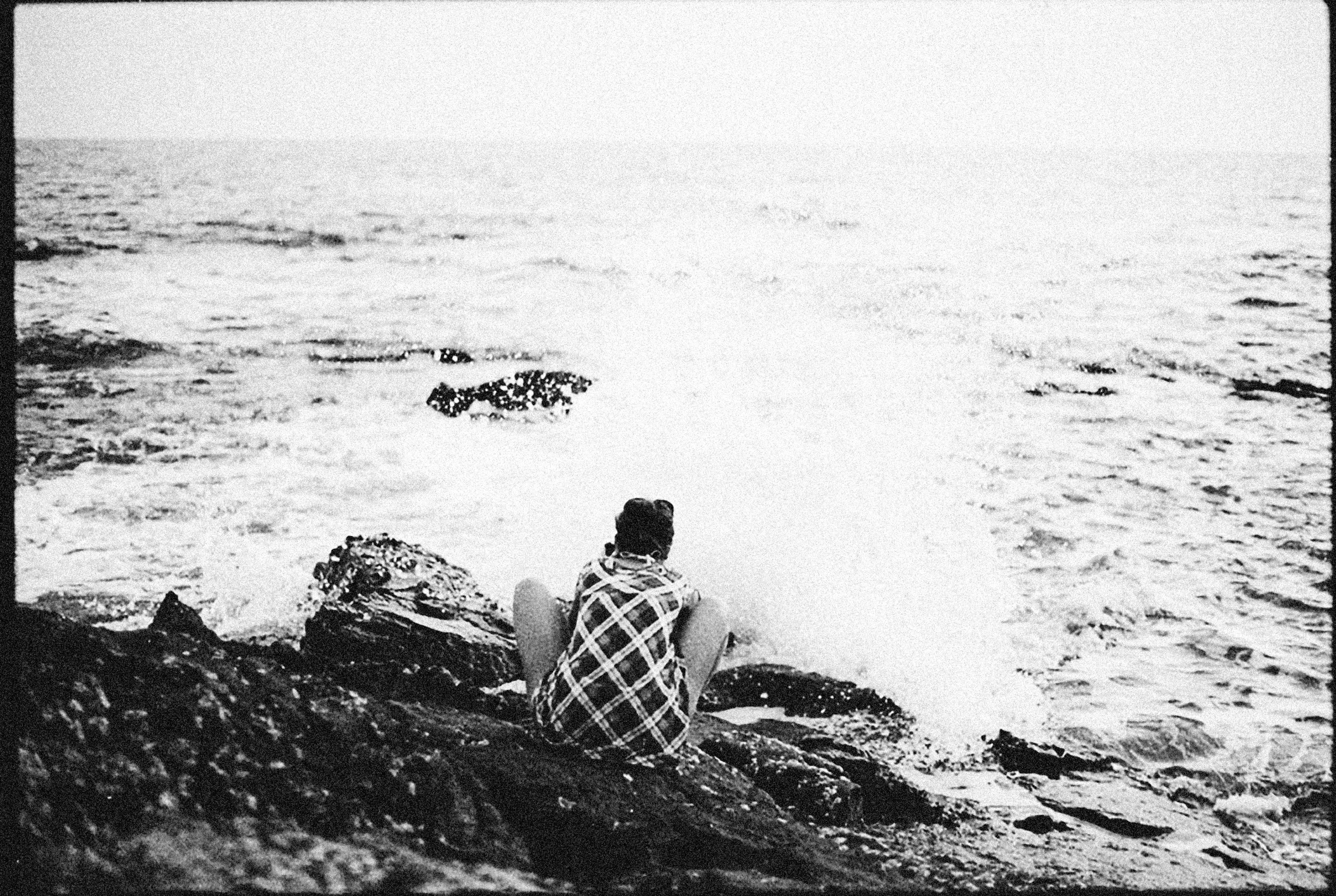 Woman Crouching on Rocks by the Sea at Dusk Holding a Glowing Orb in ...