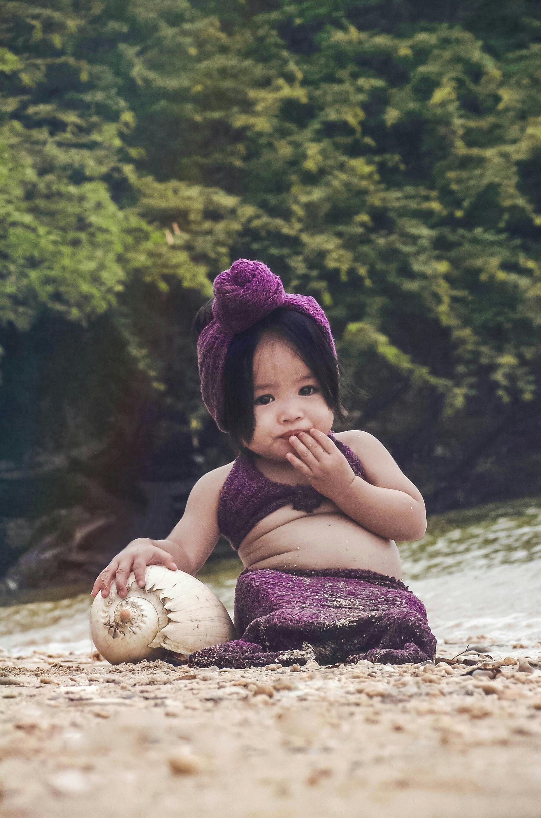 Child in Purple Mermaid Costume Sitting on Beach Sand · Free Stock Photo