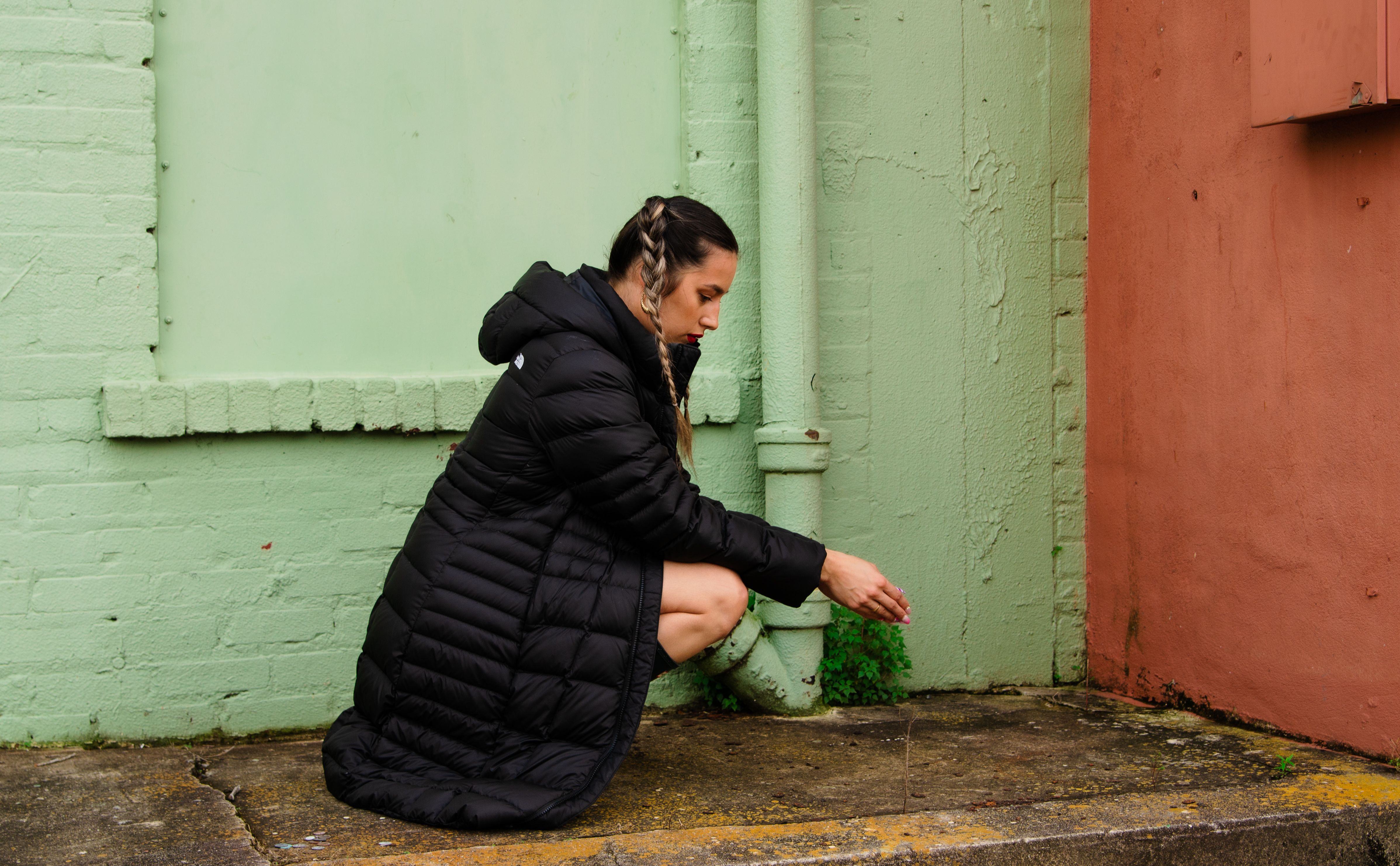 A Woman Wearing a Puffer Jacket Crouching on the Sidewalk · Free Stock ...