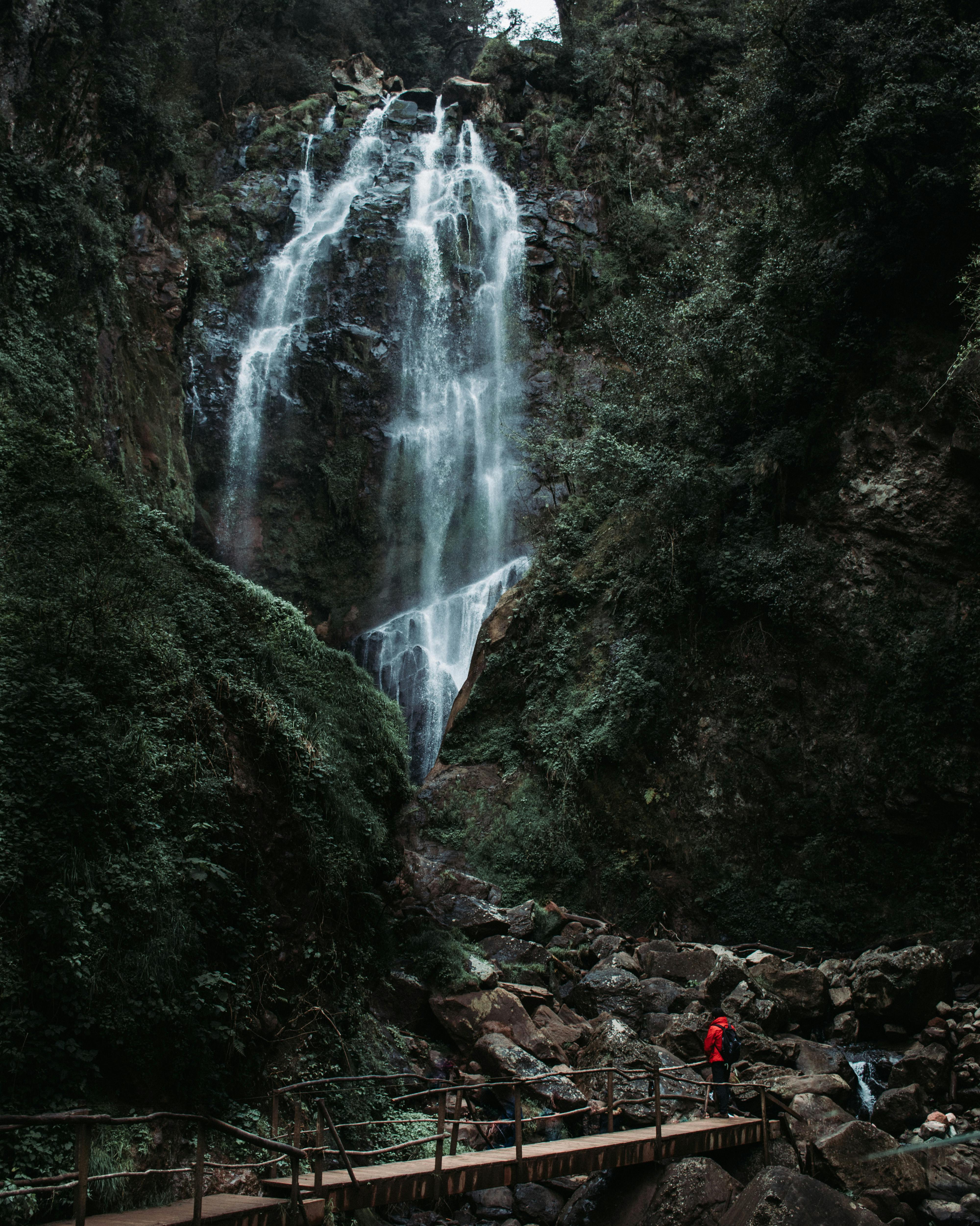 Person in Red Jacket Standing Near a Waterfalls · Free Stock Photo