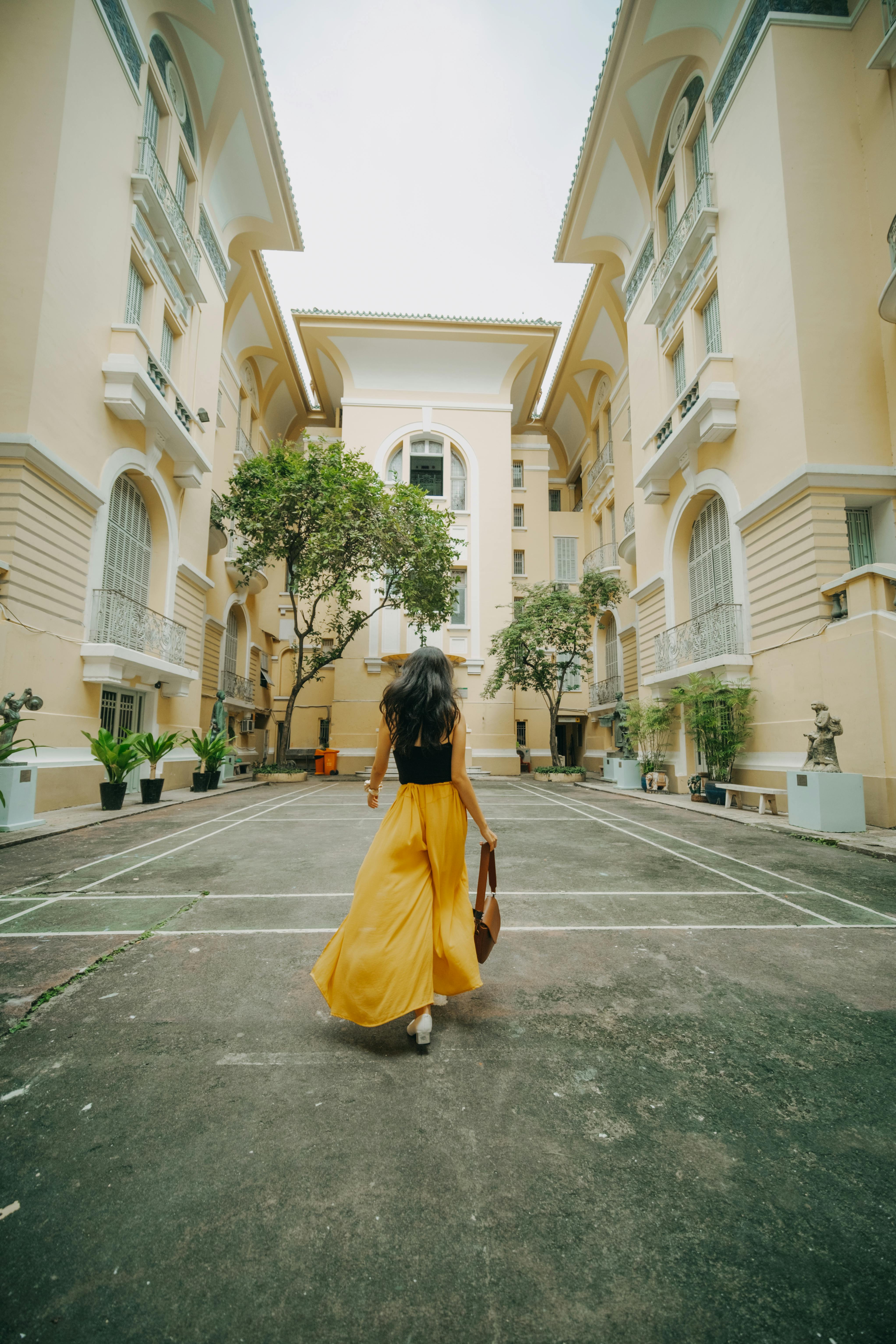 Back View of a Woman Walking Near Buildings · Free Stock Photo