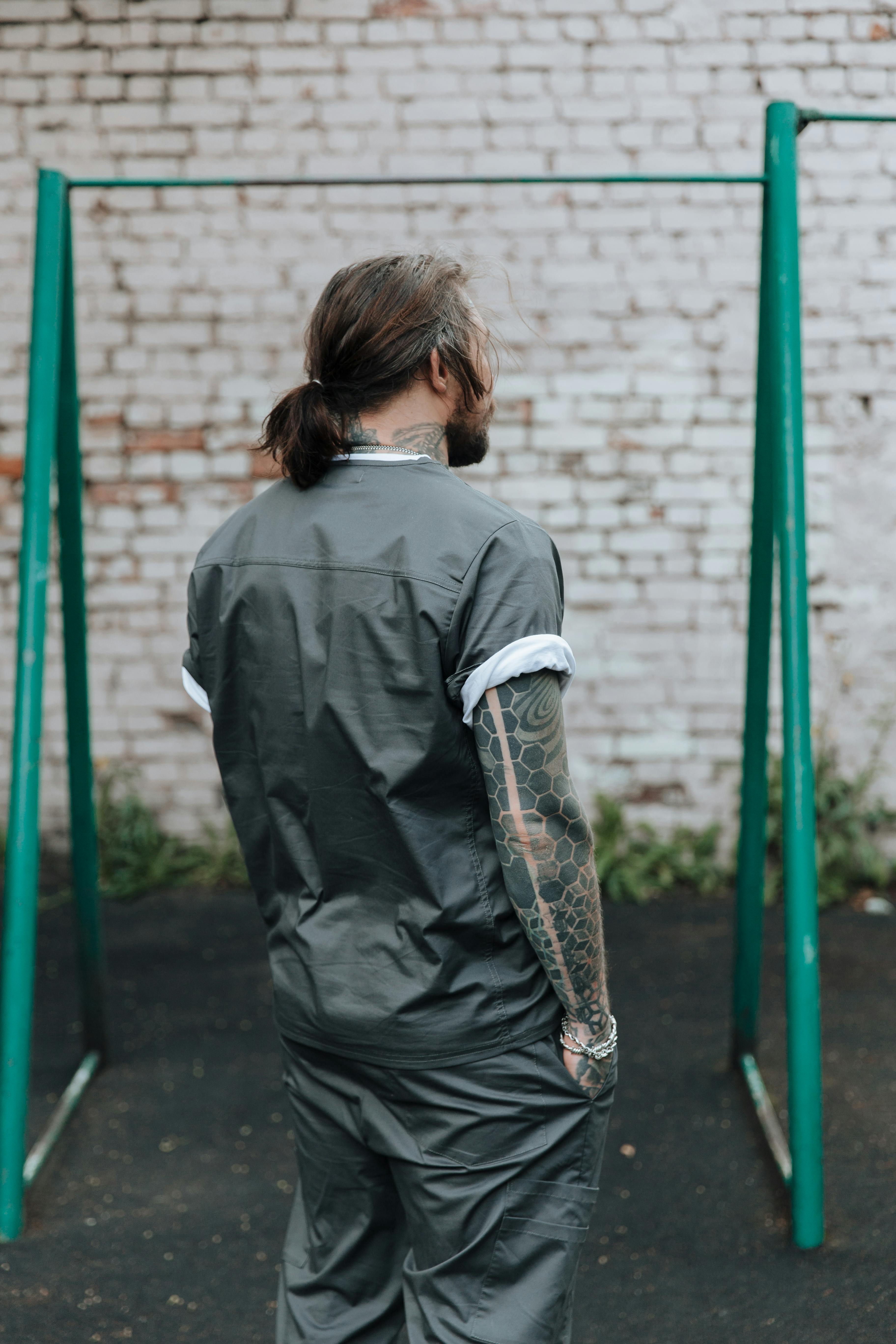 Prisoner with Tattoos and Ponytail in Jail Yard · Free Stock Photo