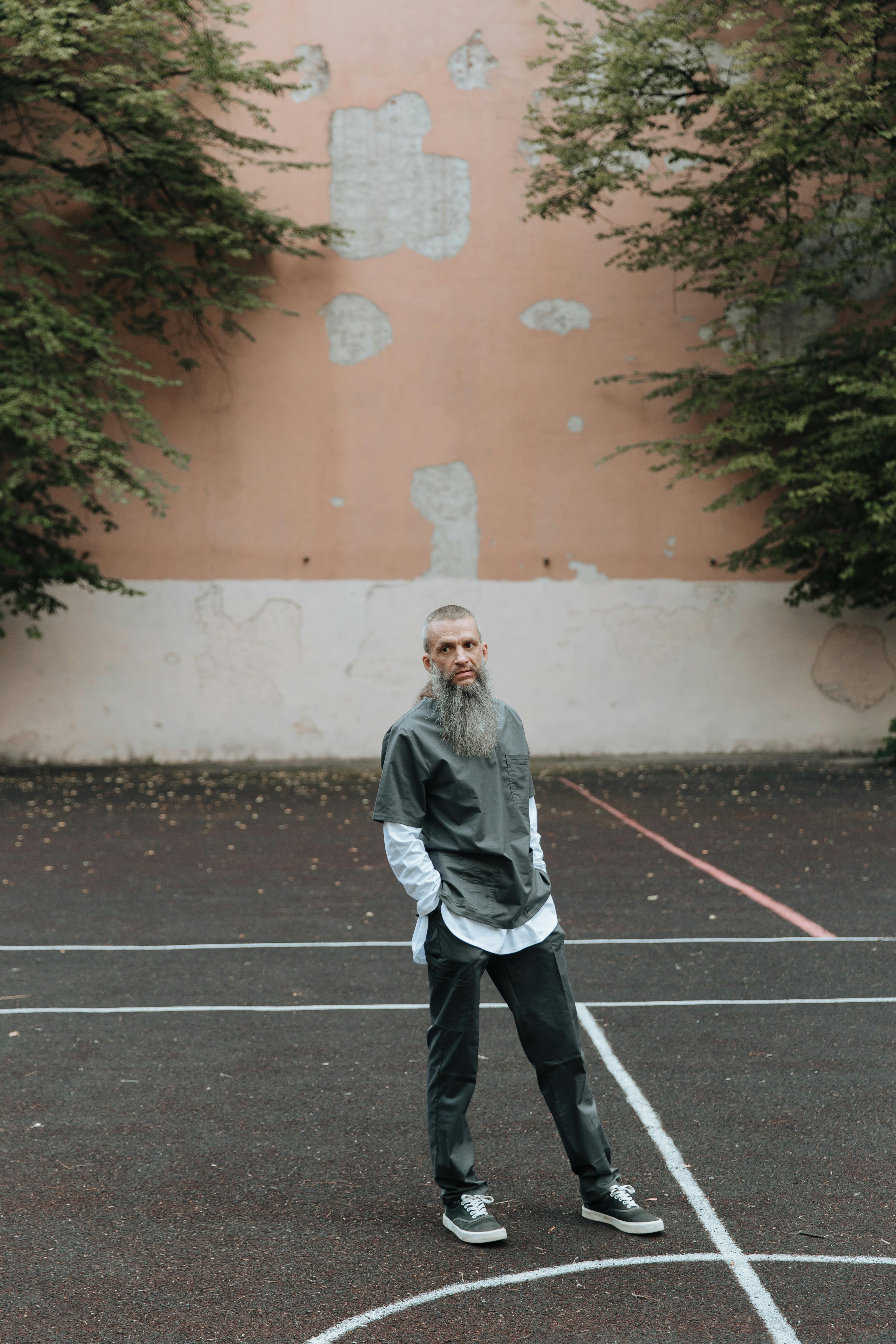 Bearded Prisoner Standing in Jail Sportsfield · Free Stock Photo